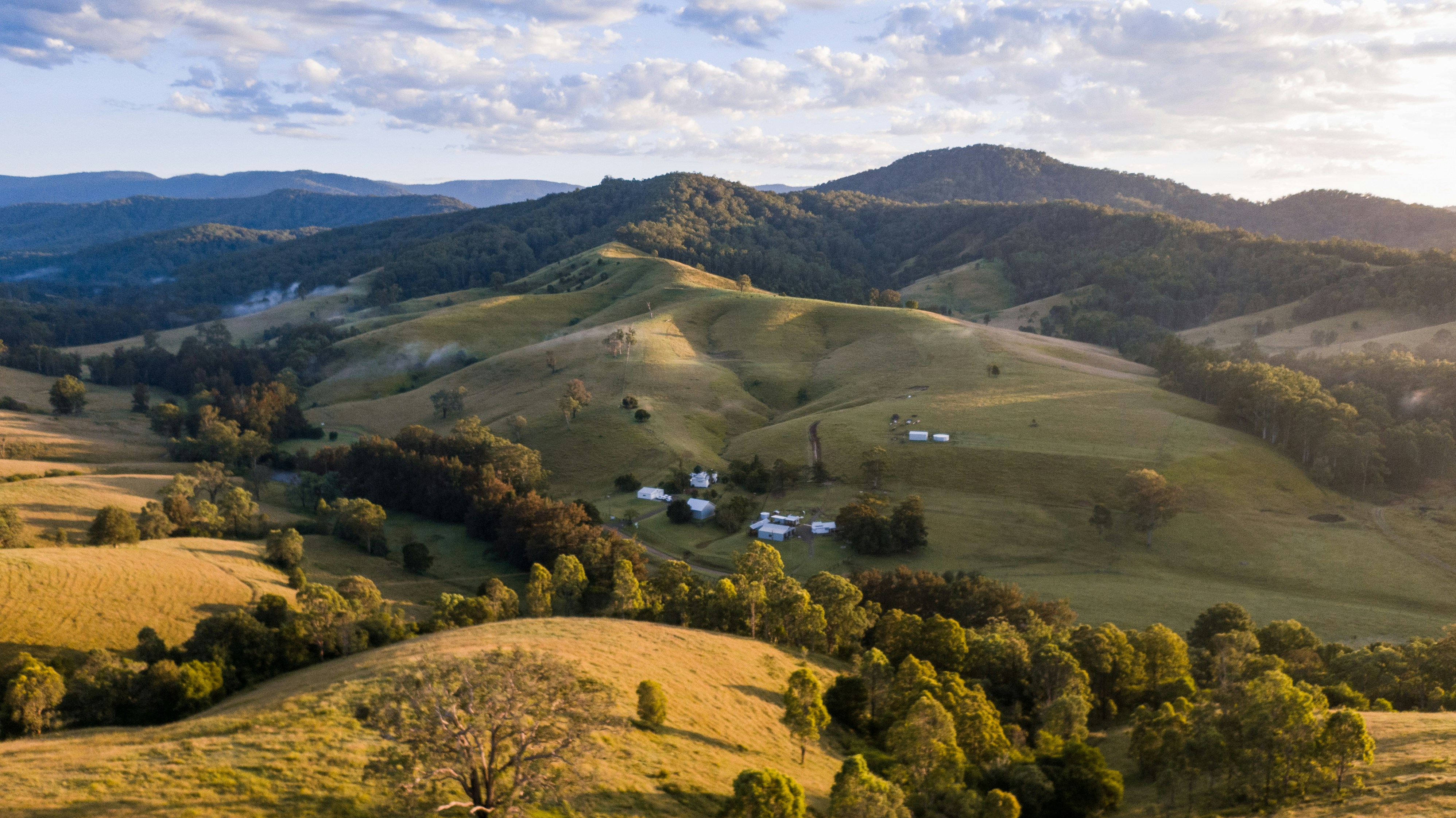 Sunlit Valleys: Dwellings Nestled Among Rolling Hills at Golden Hour