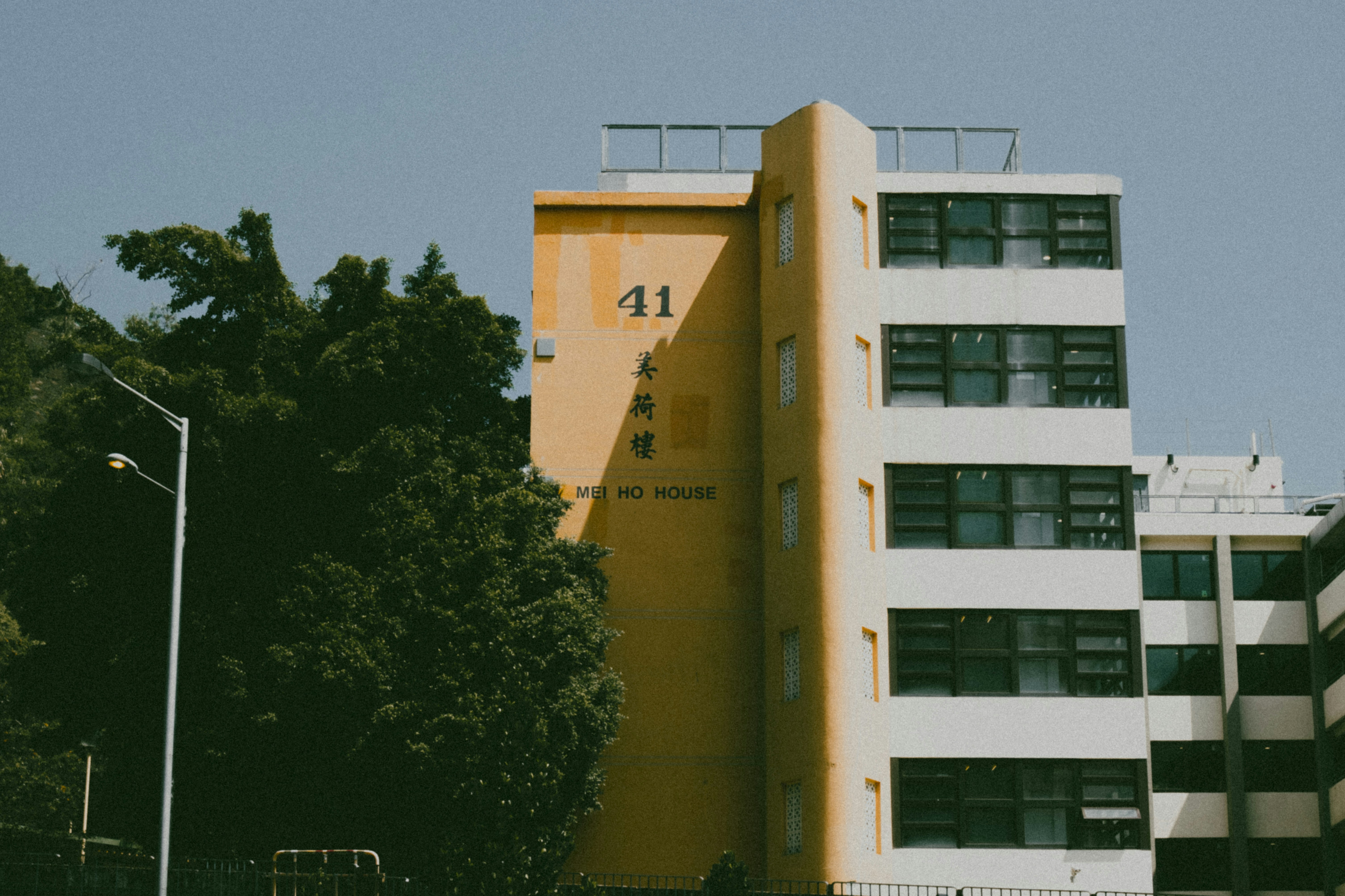 A vibrant yellow building featuring the number 41 and the name 'Mi Ho House,' partially obscured by lush greenery.
