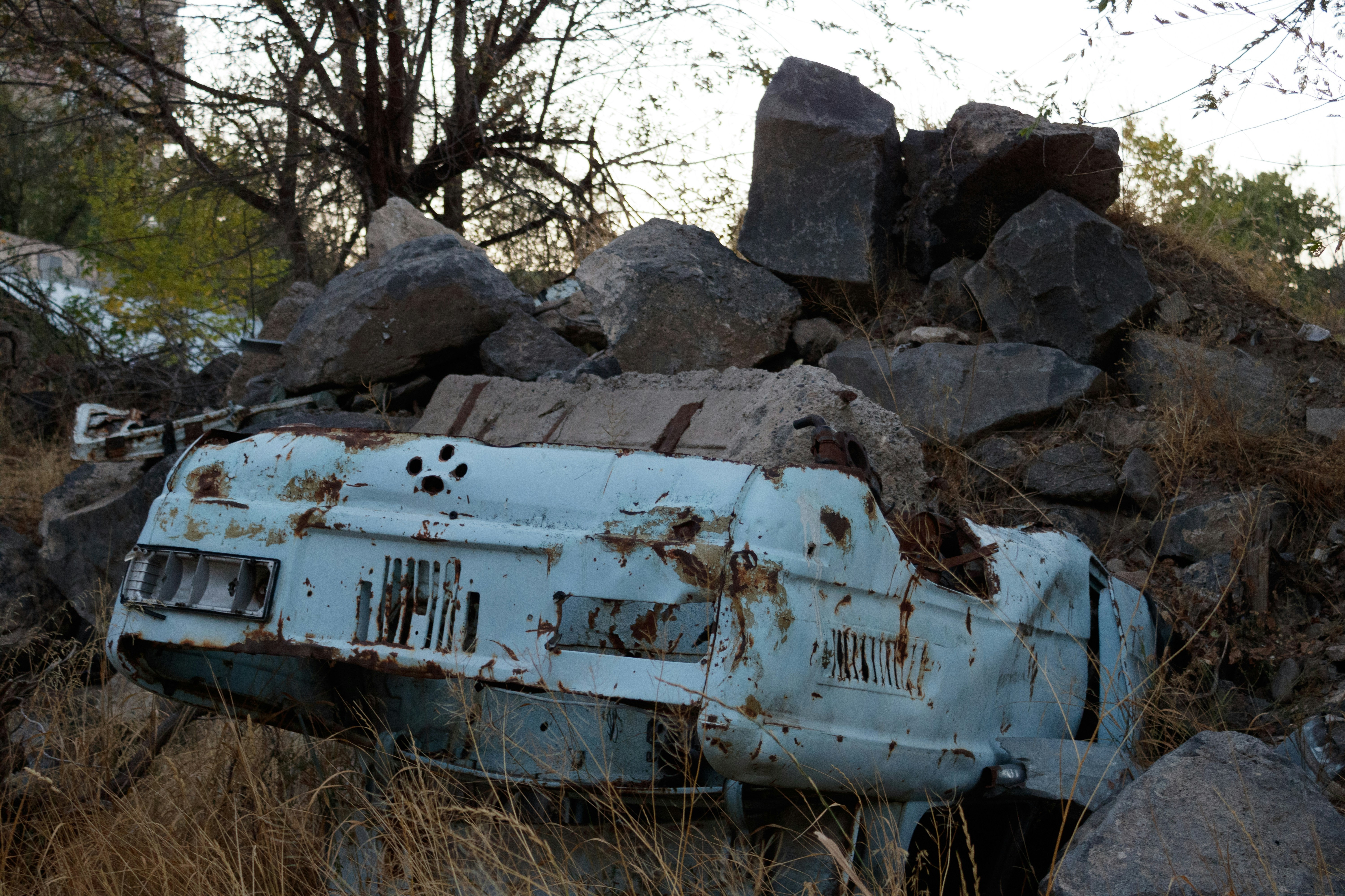 a white car with a smashed front end in a rocky area