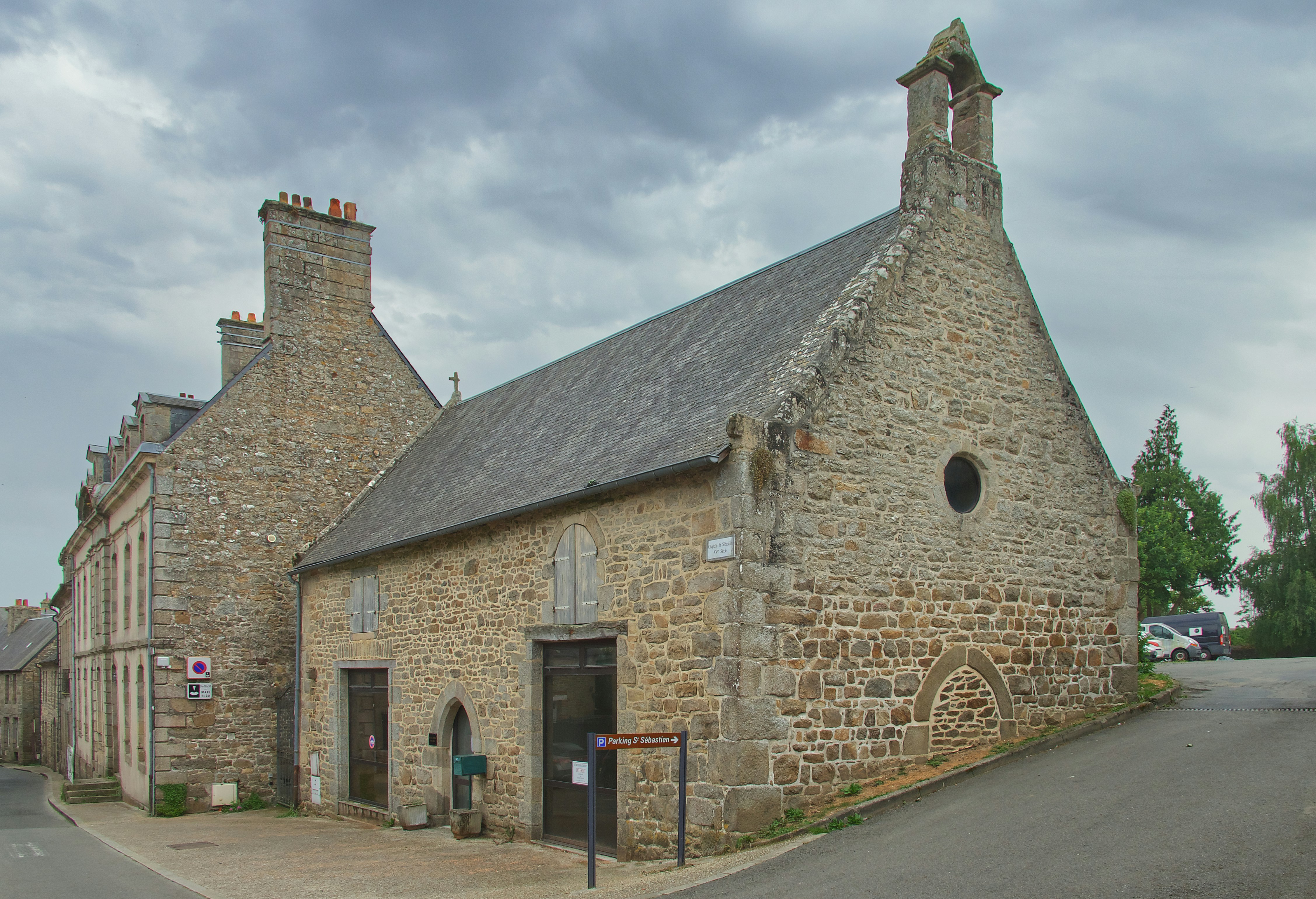 Stone chapel with arched windows and bell tower, now a medical office, under a cloudy sky.