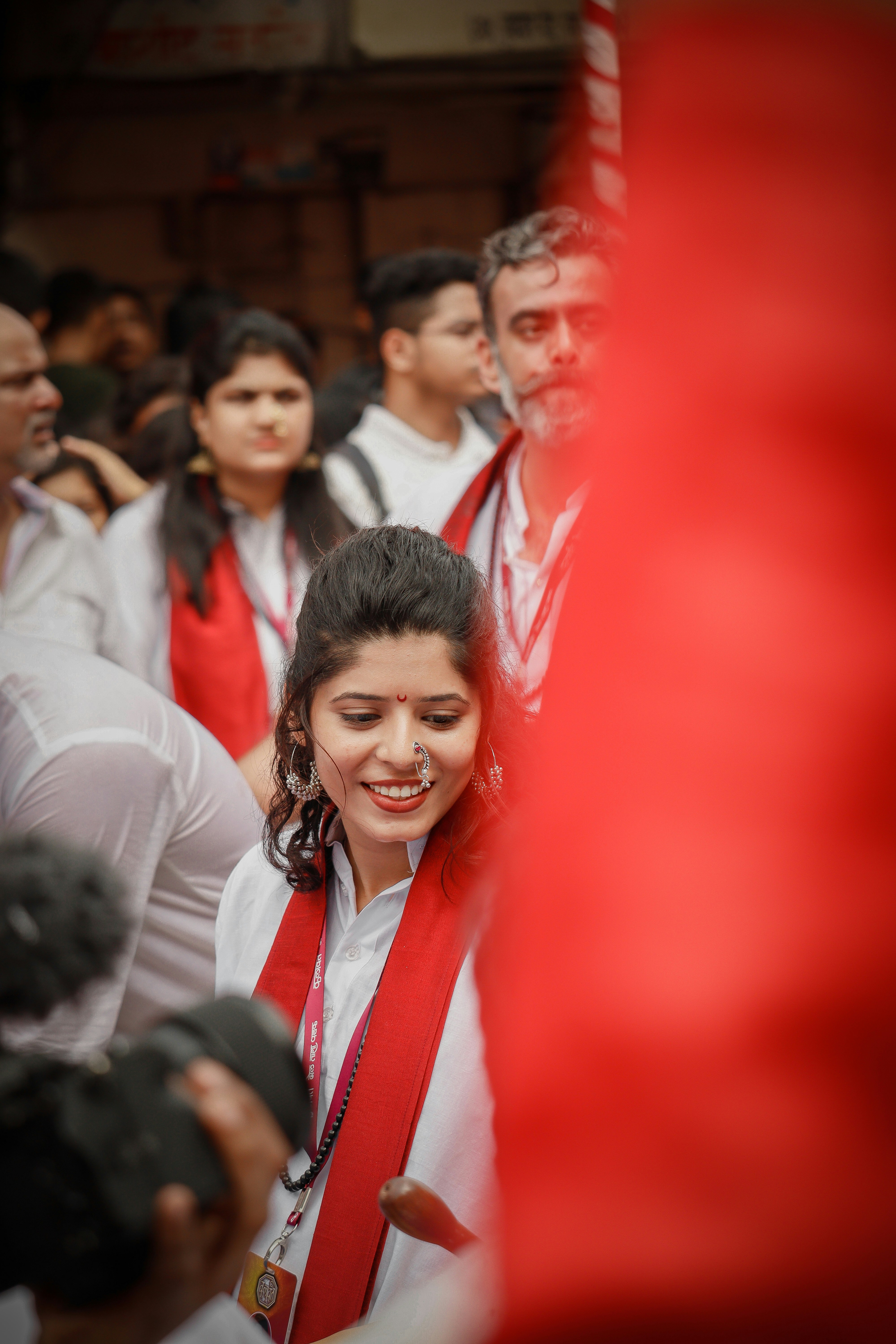 Scarlet Sash Serenity: A Subtle Smile Amid the Crowd