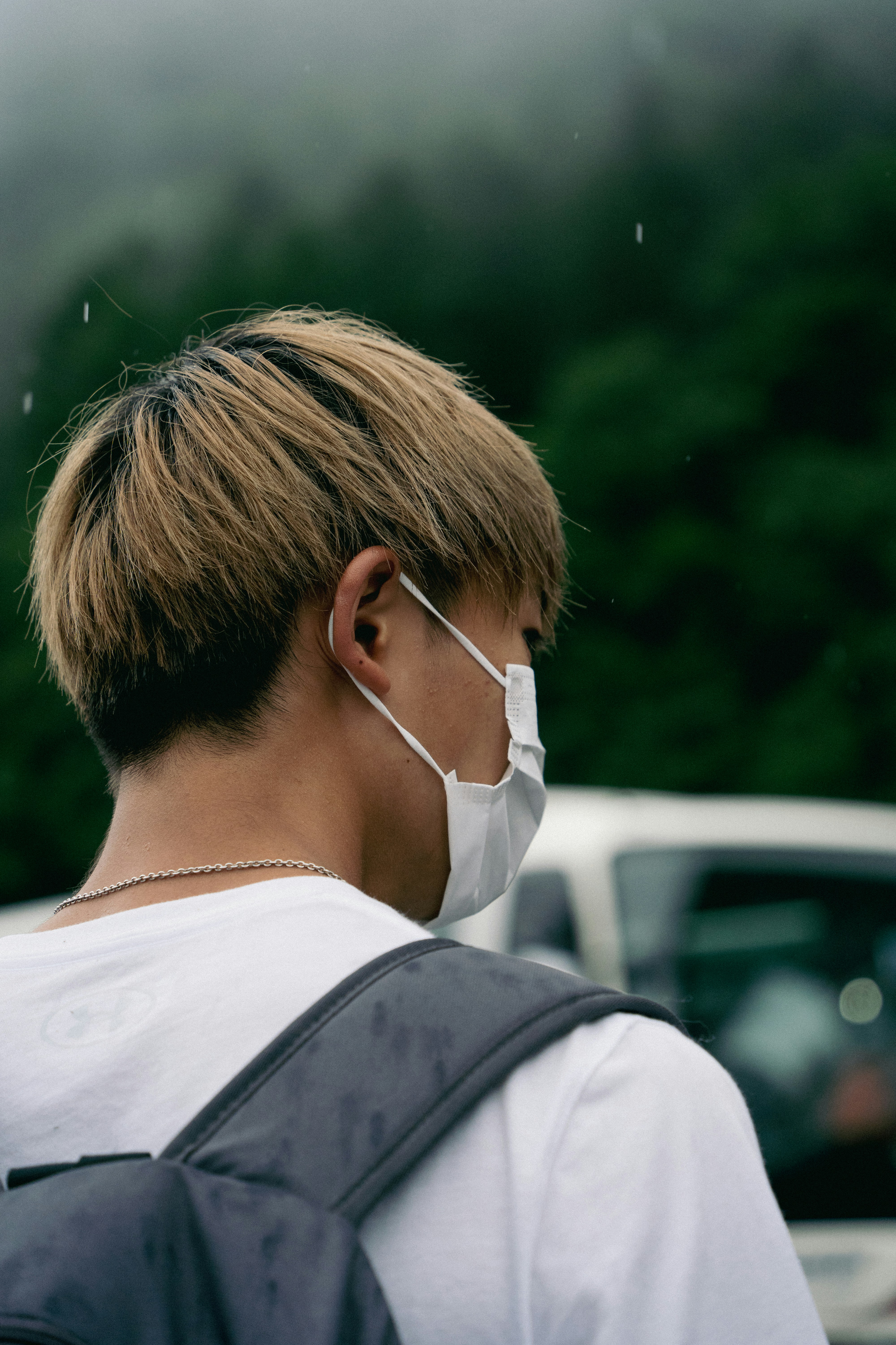Back-turned in the Rain: A Masked Moment with a Quiet Street Backdrop