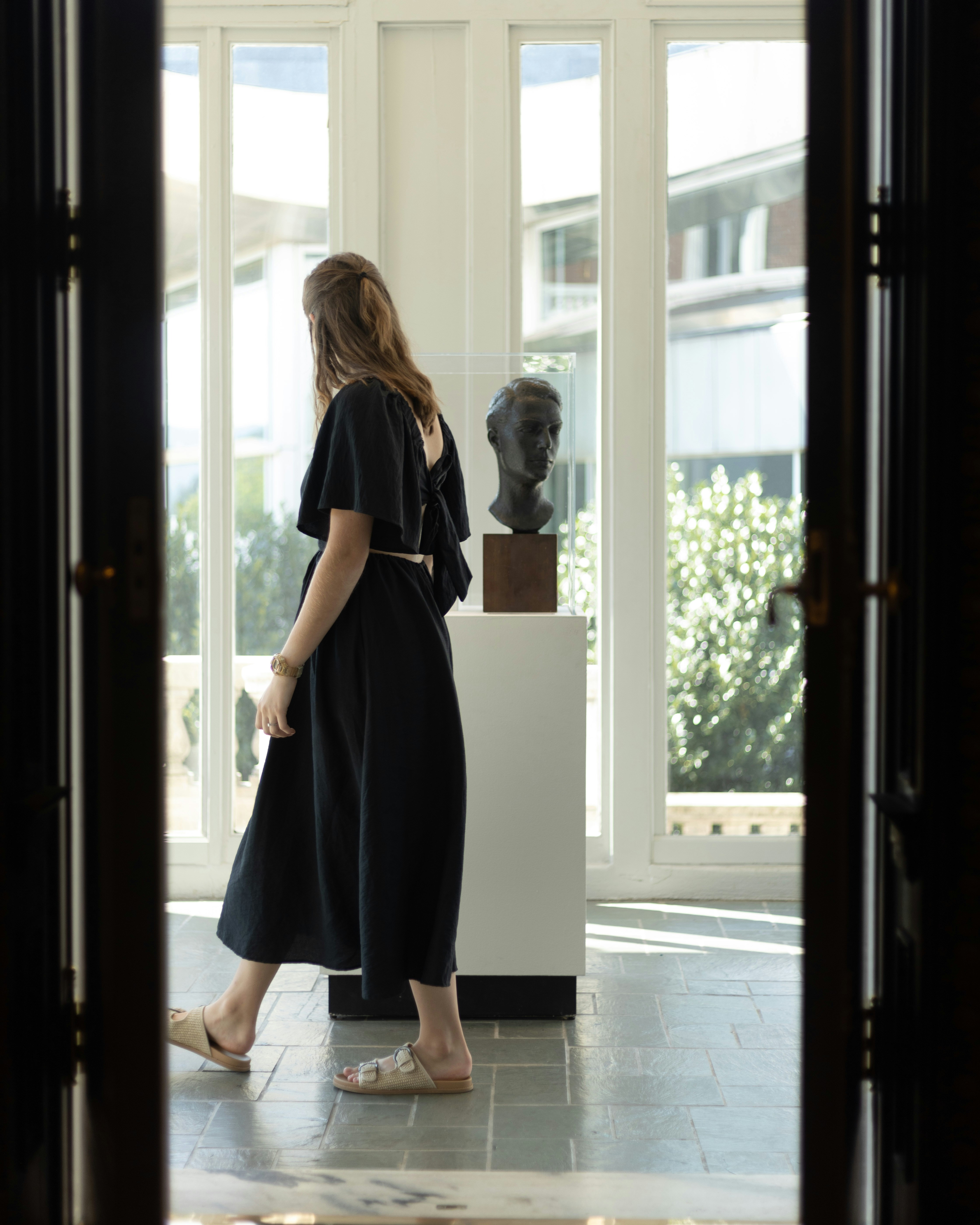 Between Glass and Bronze: A Woman in a Museum Corridor