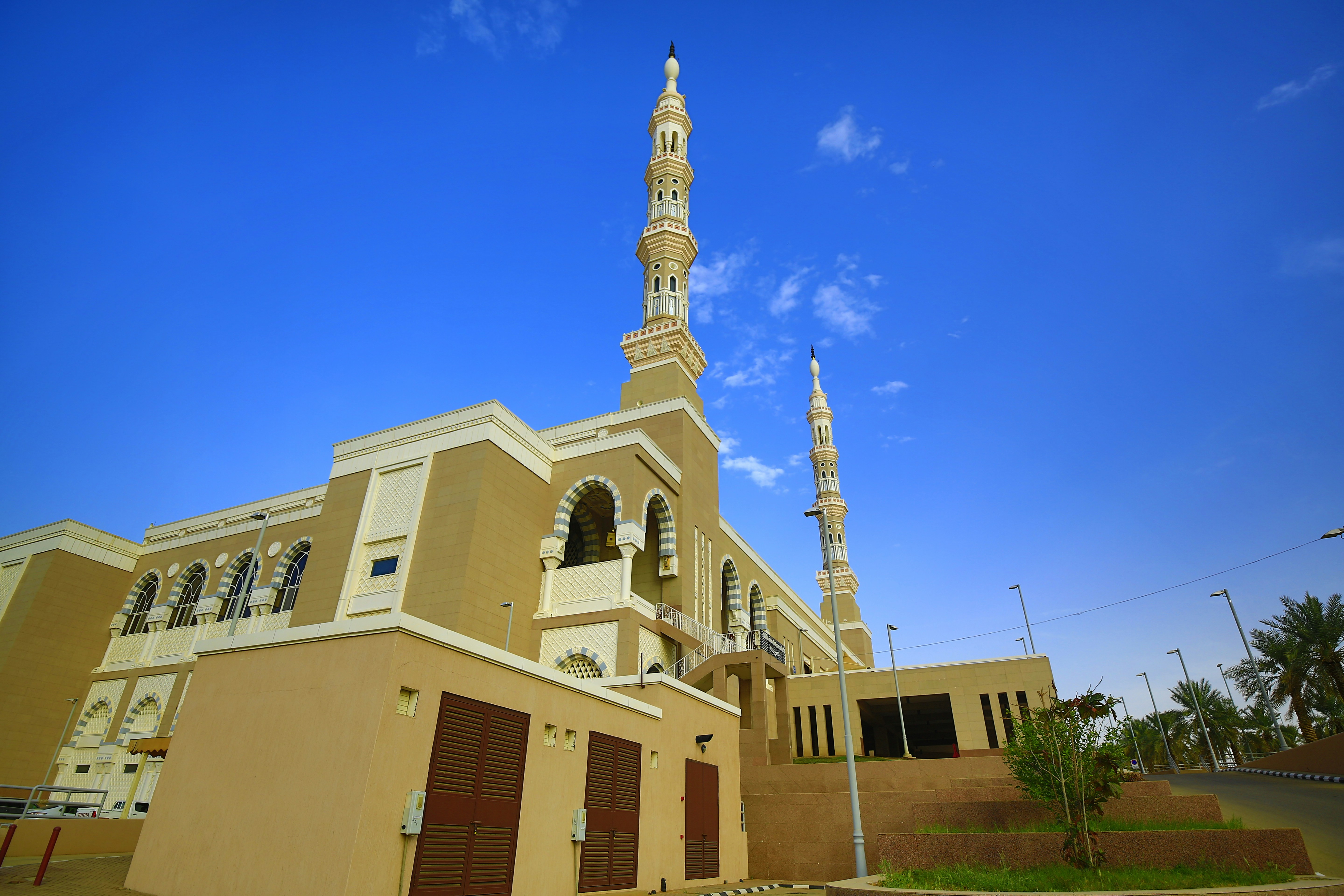 Majestic mosque with towering minarets against a clear blue sky, showcasing intricate architectural details and serene surroundings.