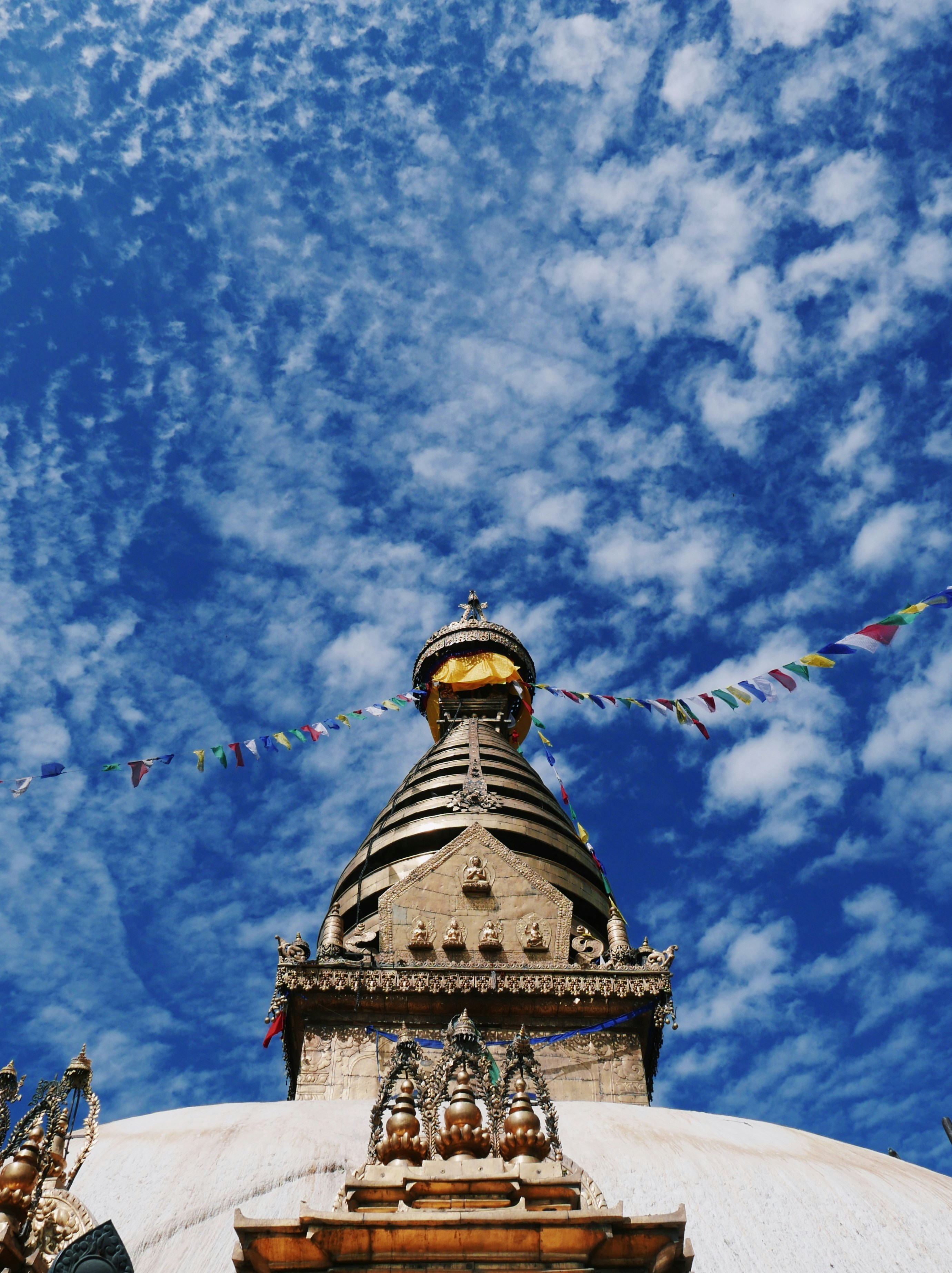 A majestic stupa rises against a vibrant blue sky, adorned with colorful prayer flags that flutter in the breeze.