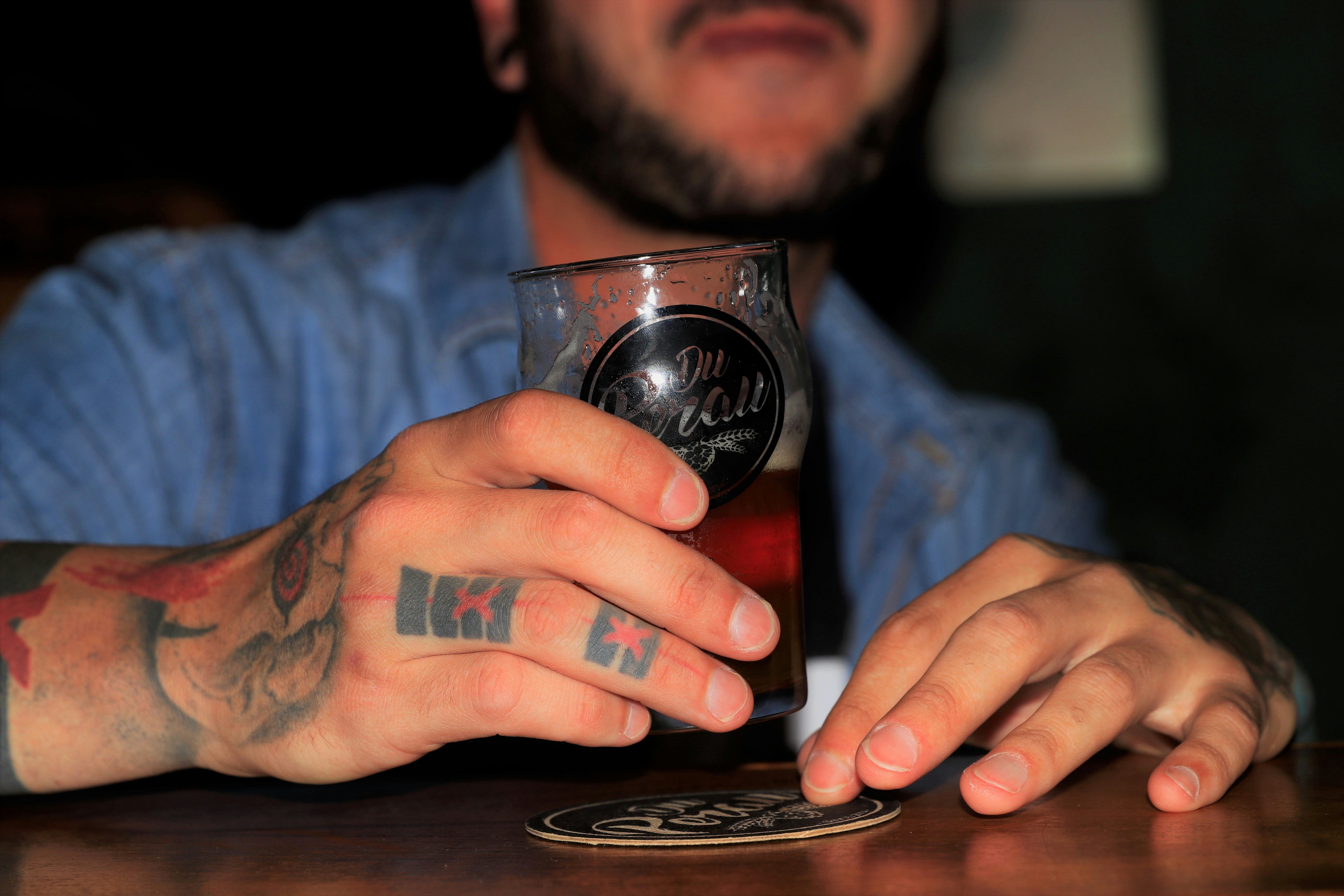 Ink and Amber at the Bar: A Close-Up of Tattooed Hands and a Glass