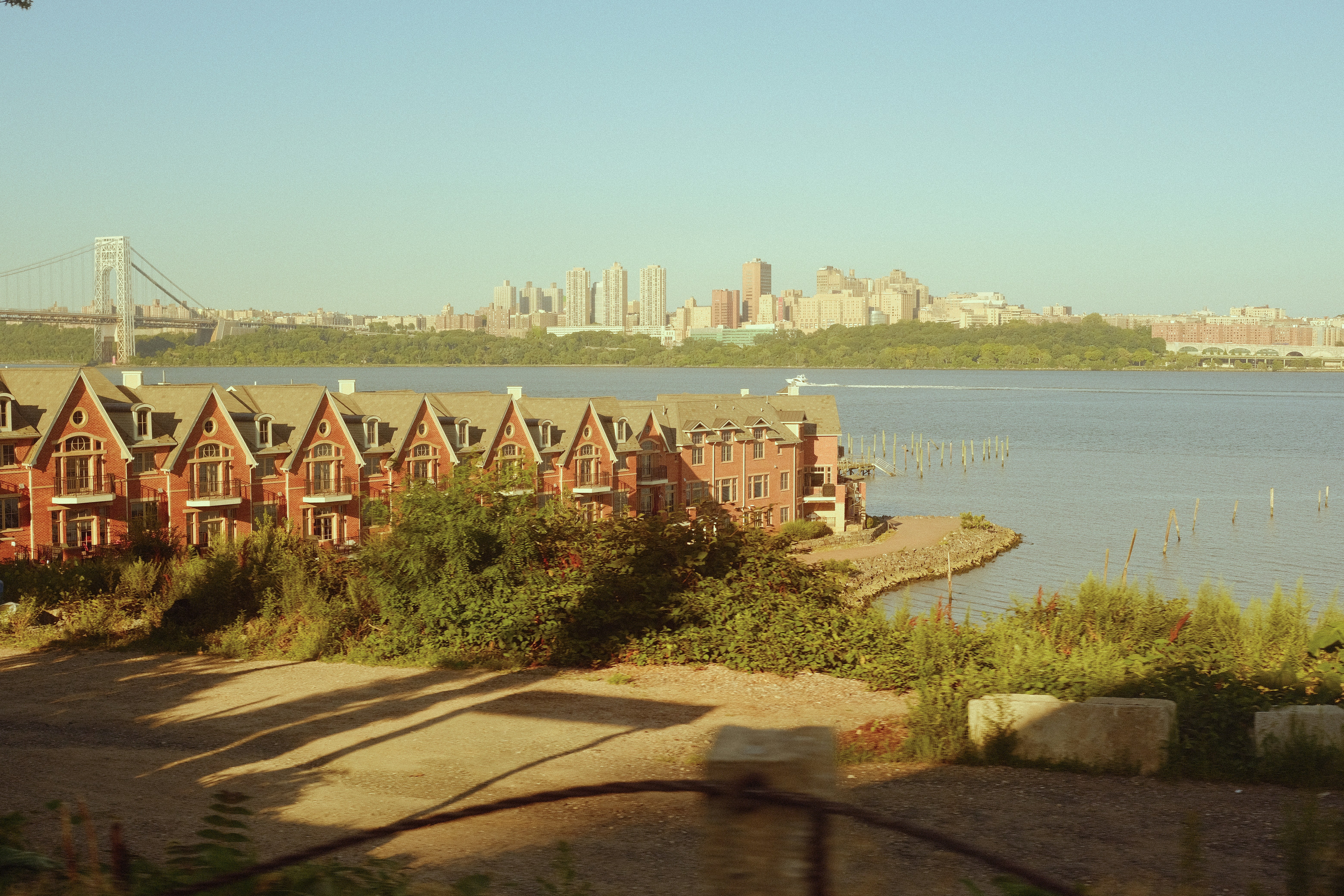 Row of brick cottages by the river with distant city skyline