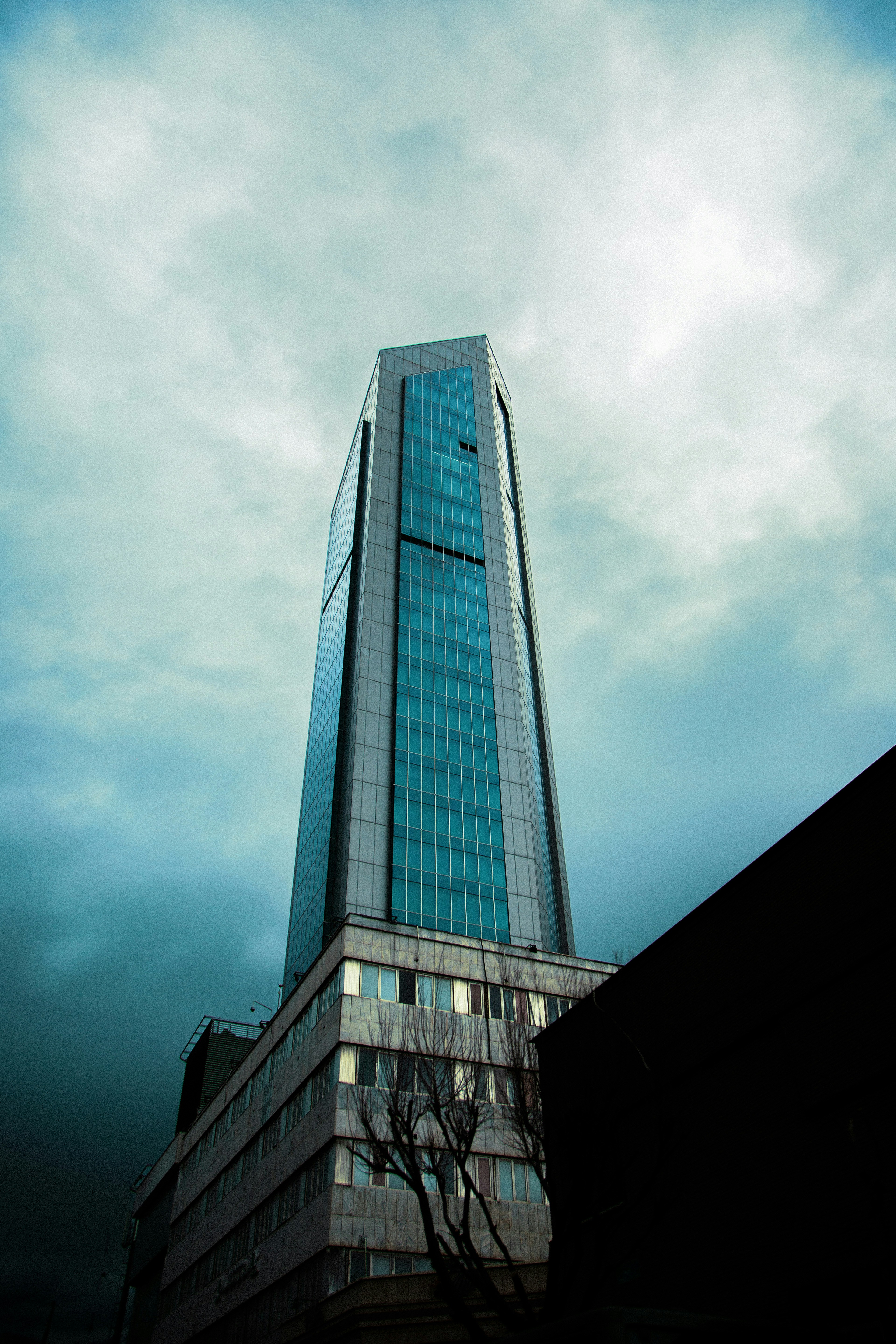 A sleek skyscraper rises against a dramatic sky, showcasing its glass facade and architectural design. The building stands as a testament to contemporary urban development.