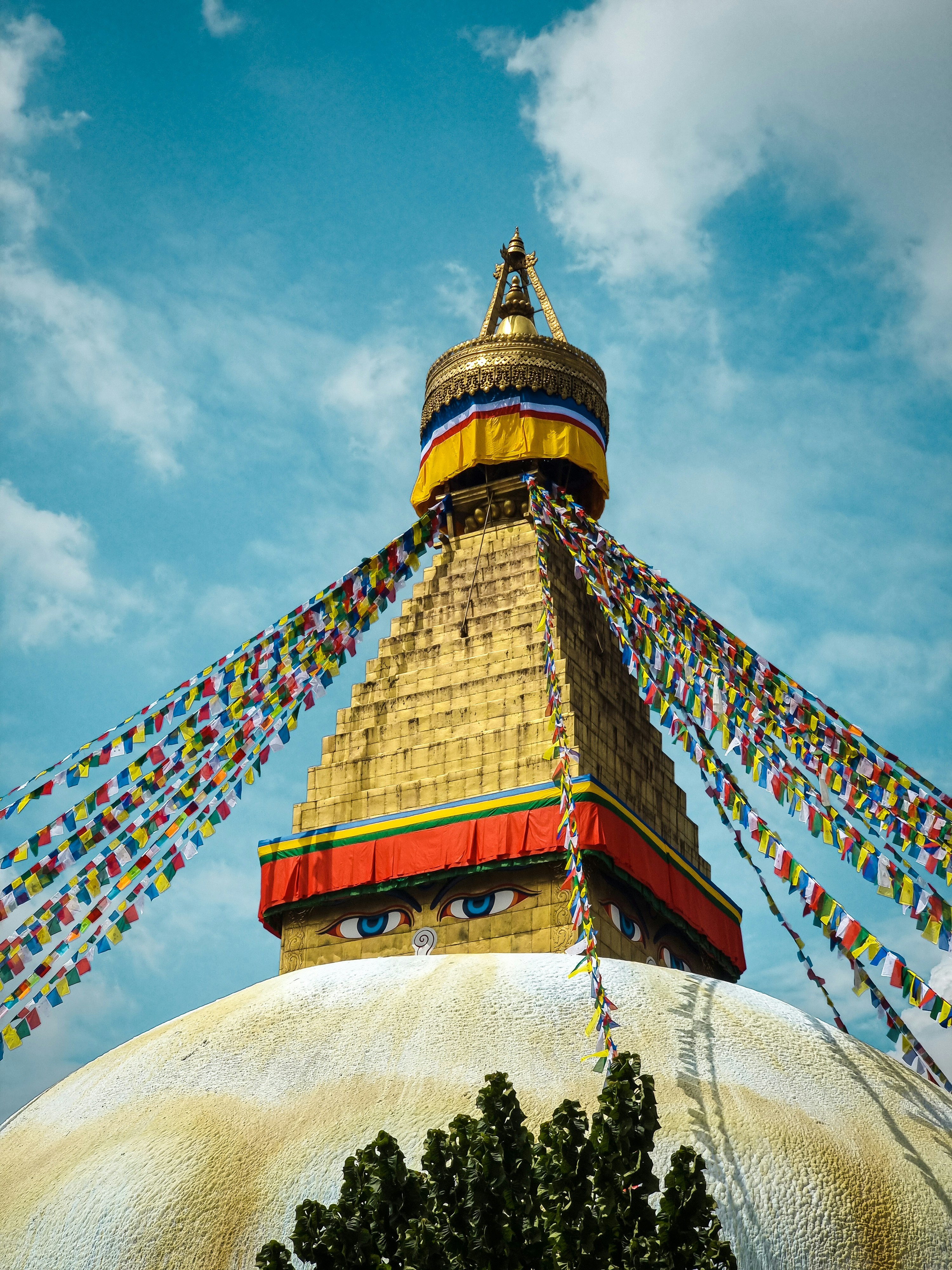 A colorful building with a gold roof with Boudhanath in the background ...