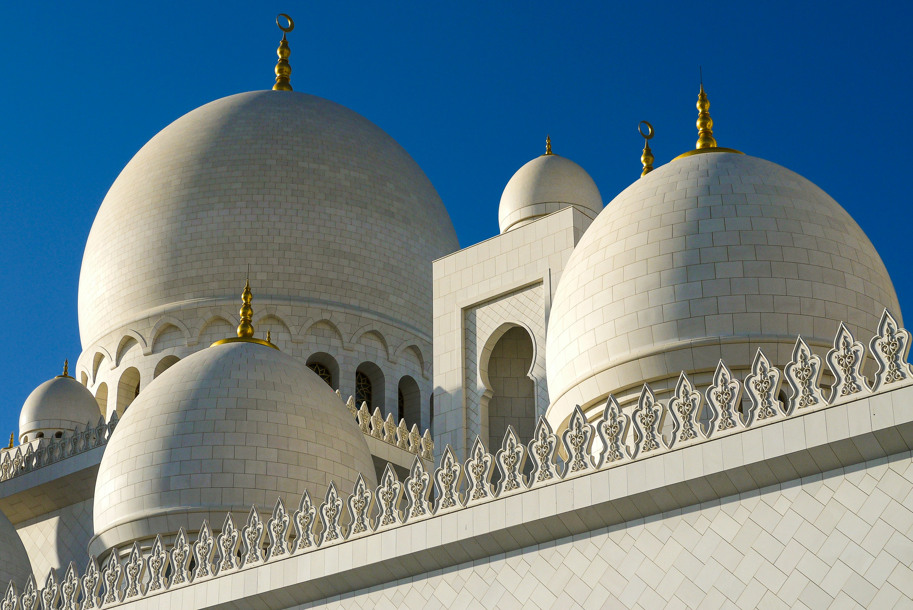 A white building with domed roofs with Sheikh Zayed Mosque in the ...