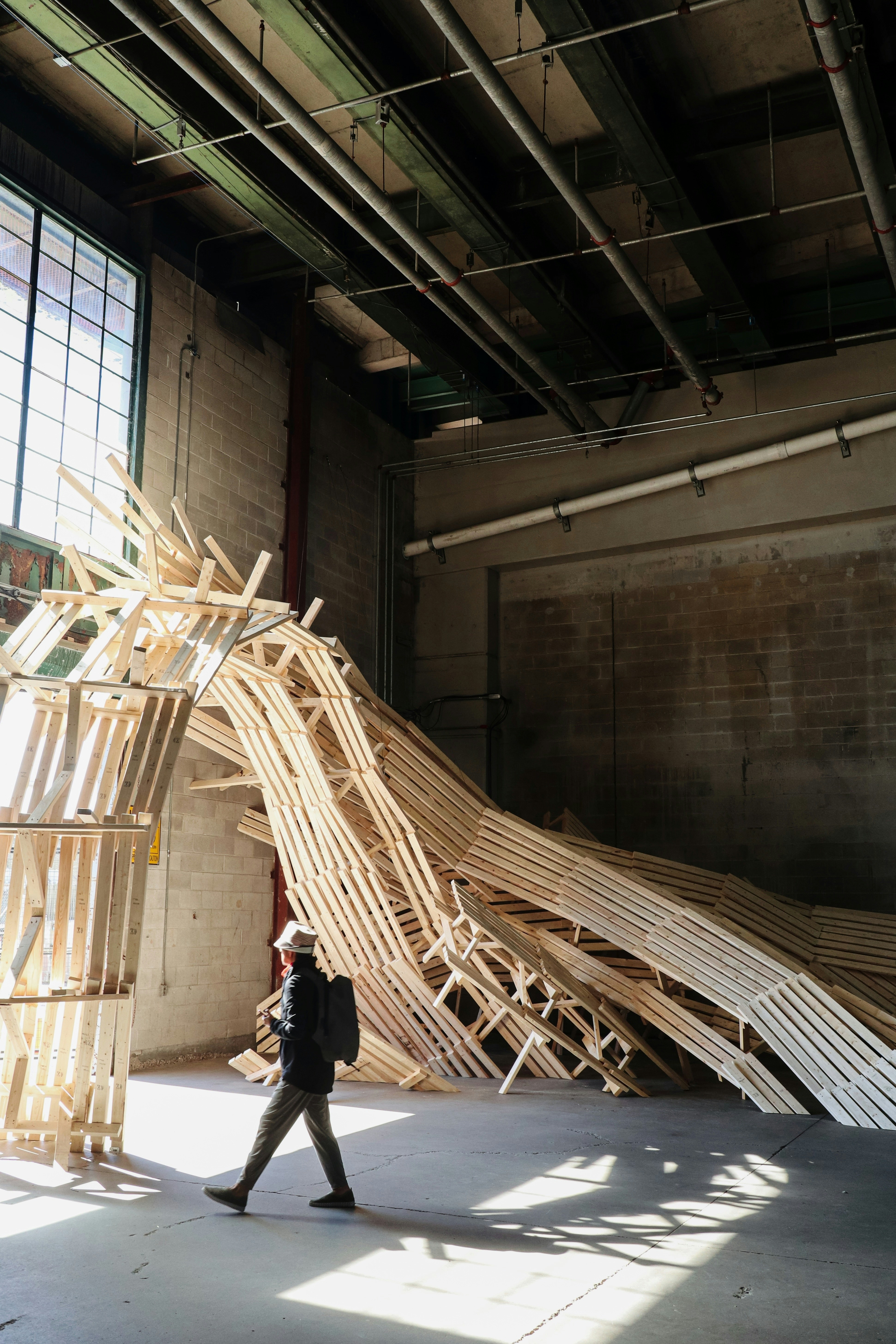 Worker Beneath a Sunlit Timber Arch in an Industrial Warehouse