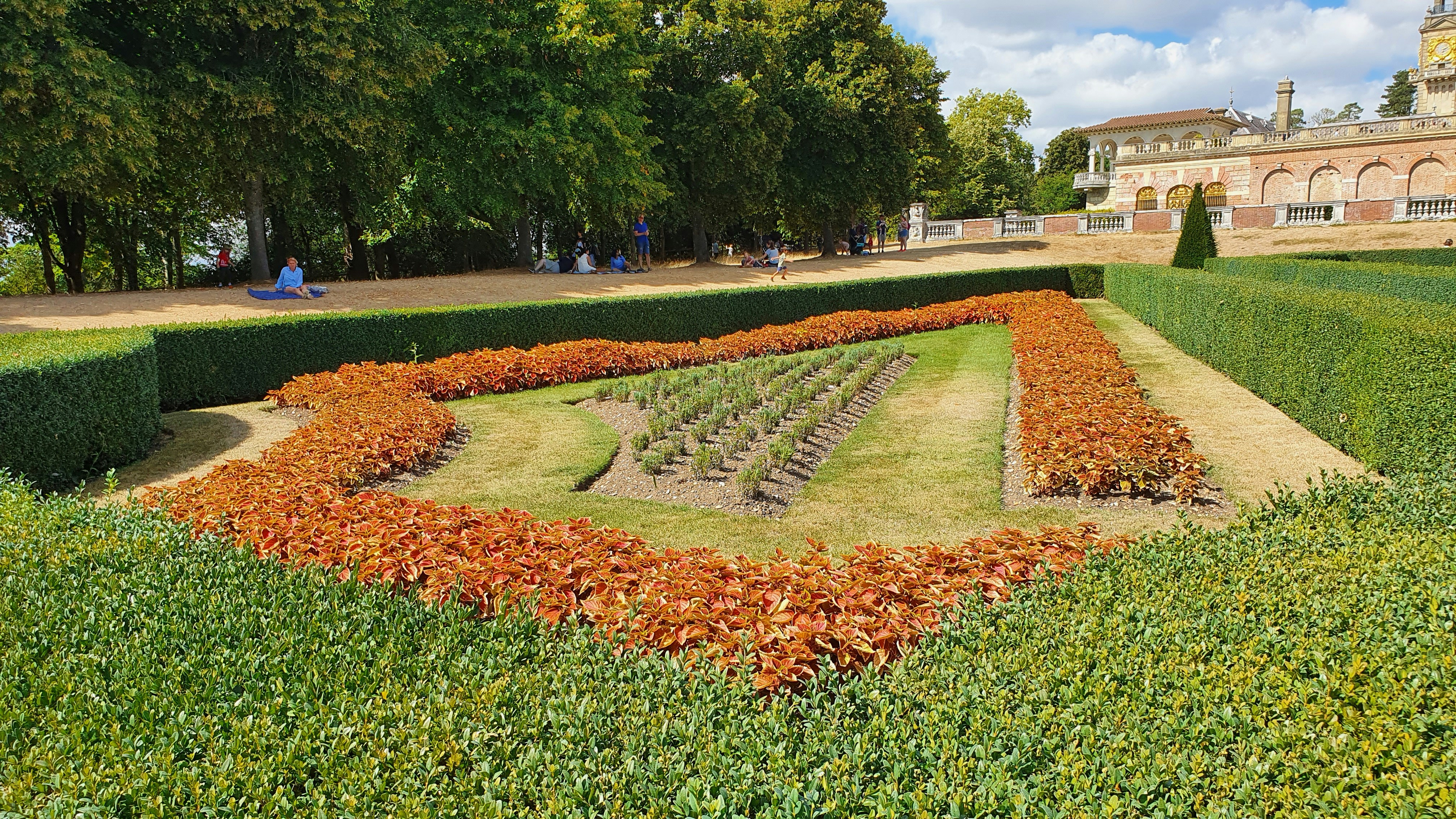 A meticulously designed garden featuring vibrant autumn foliage and geometric plant arrangements. The scene invites a tranquil exploration of nature's artistry.