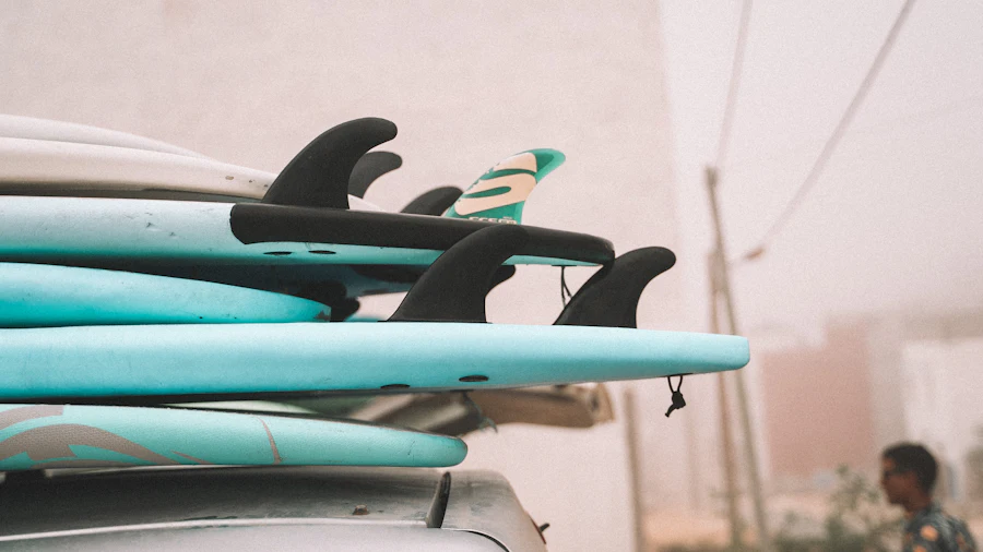 A stack of vibrant surfboards rests atop a vehicle, hinting at a day of adventure at the beach. The foggy backdrop adds a serene atmosphere.