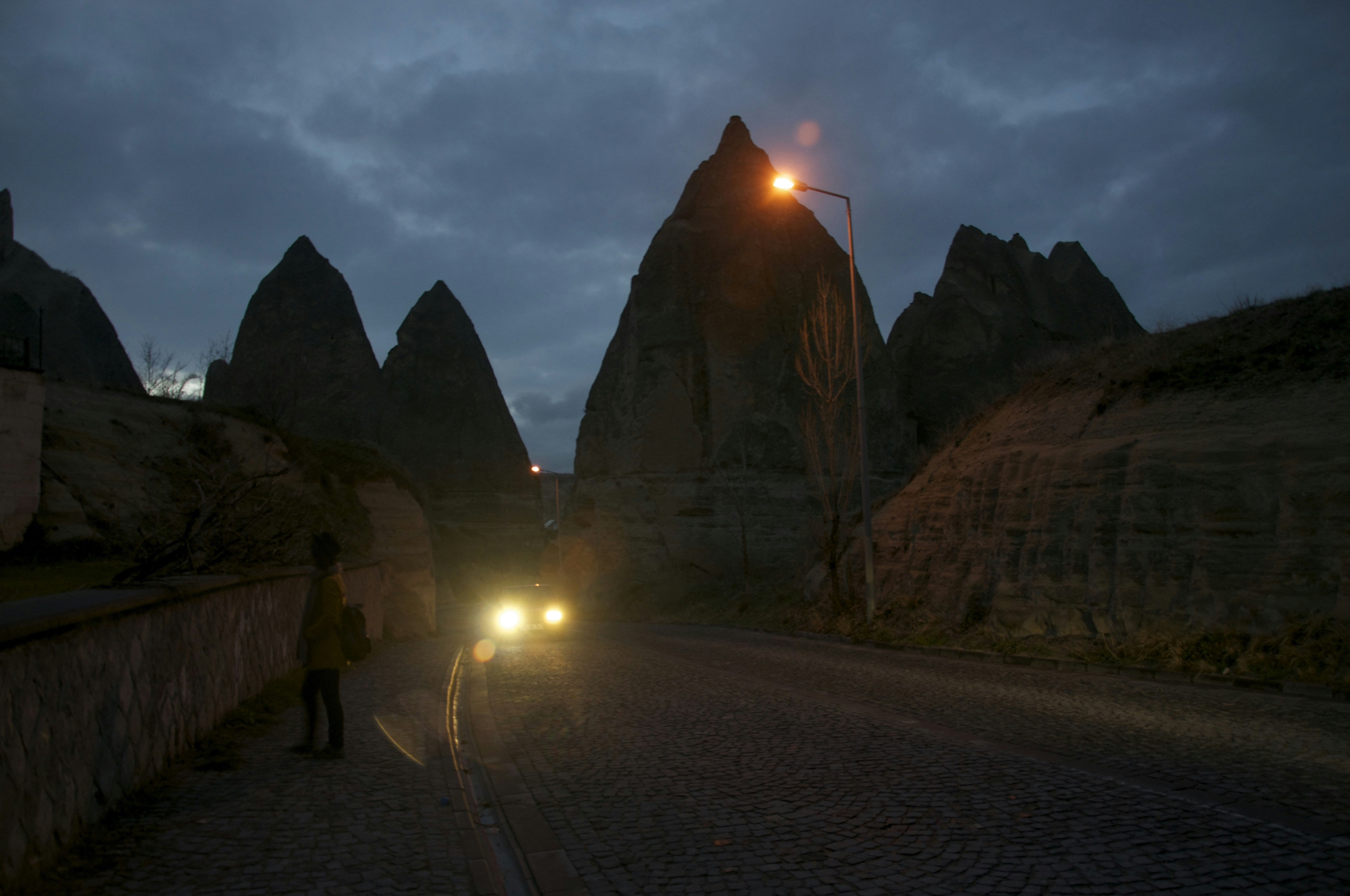 Night Road Between Sentinel Spires and a Glowing Streetlamp