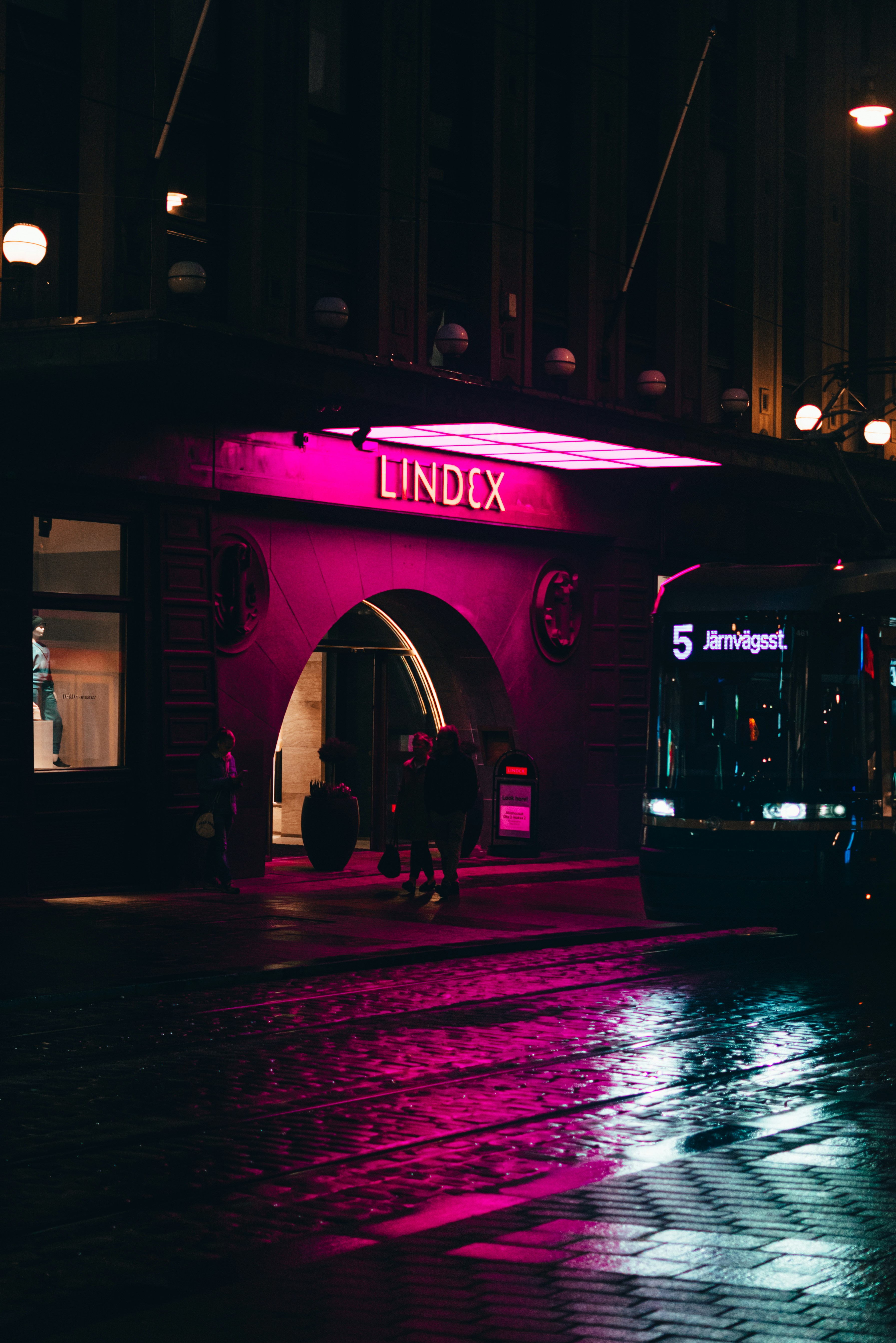 Pink Neon Anthem: LINDEX Sign Illuminates a Rain-Slick City Street
