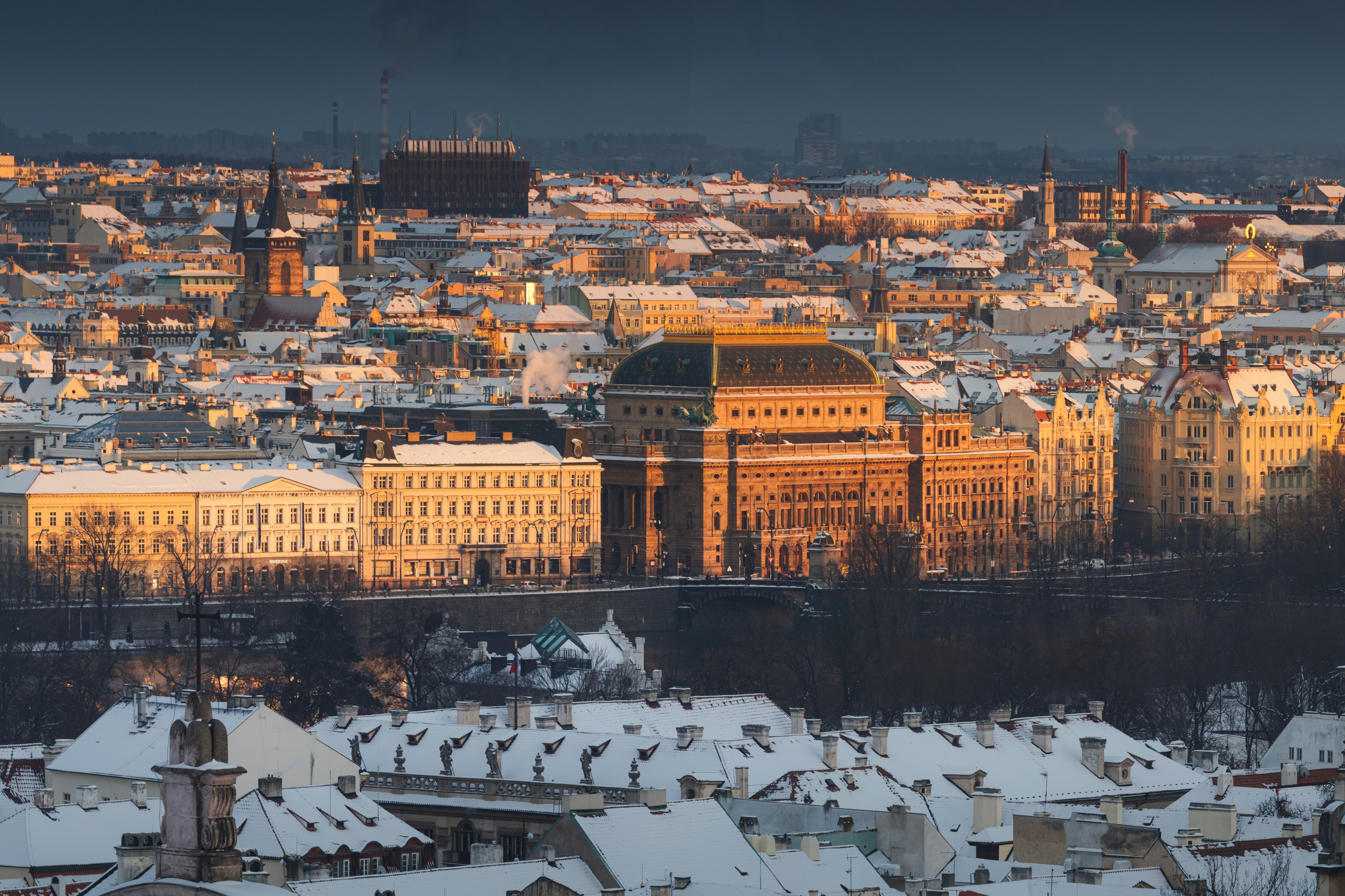 Sunlit historic buildings in a snow-draped cityscape at dusk.