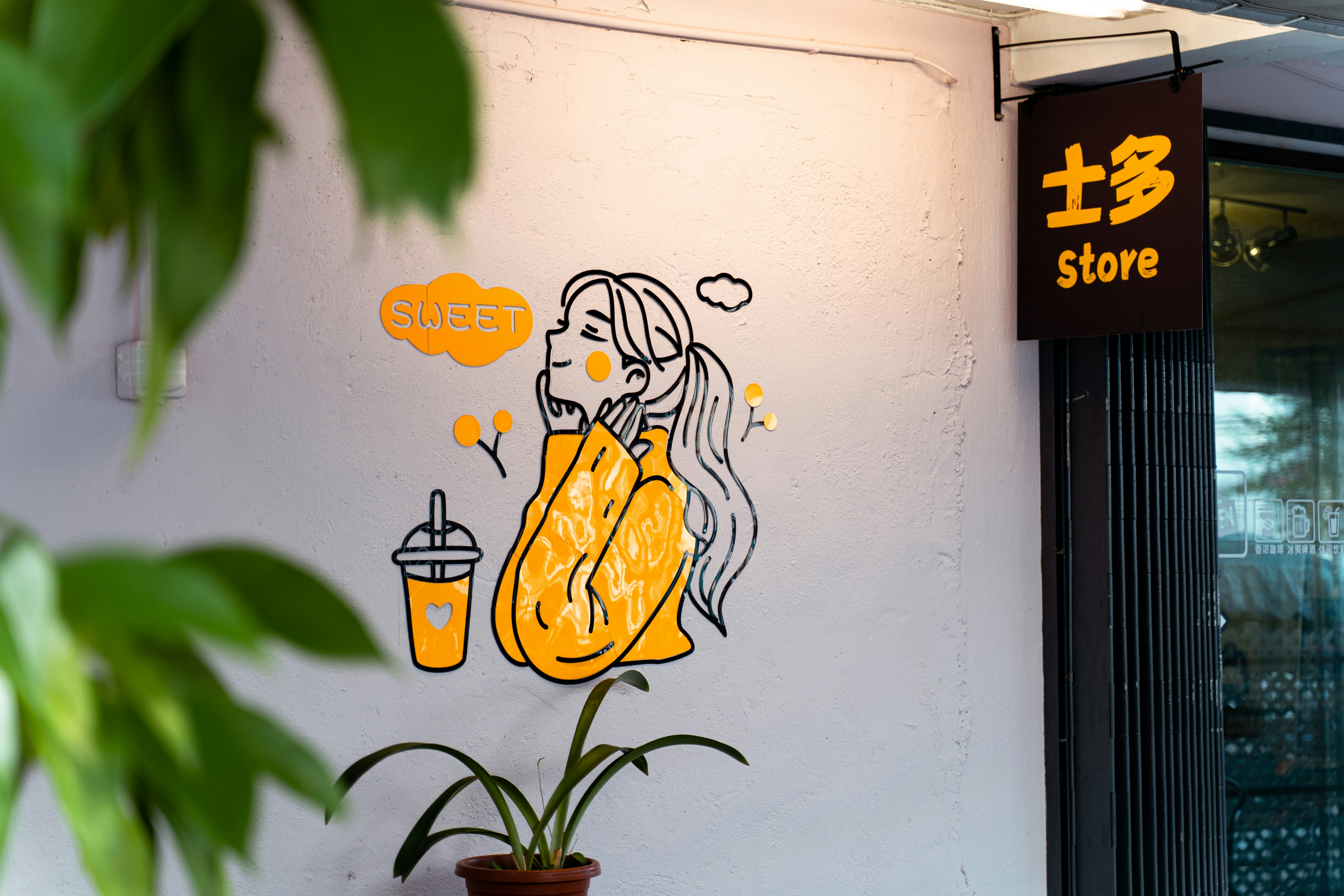 Pastel mural of a girl in an orange sweater sipping a to-go cup beside a storefront