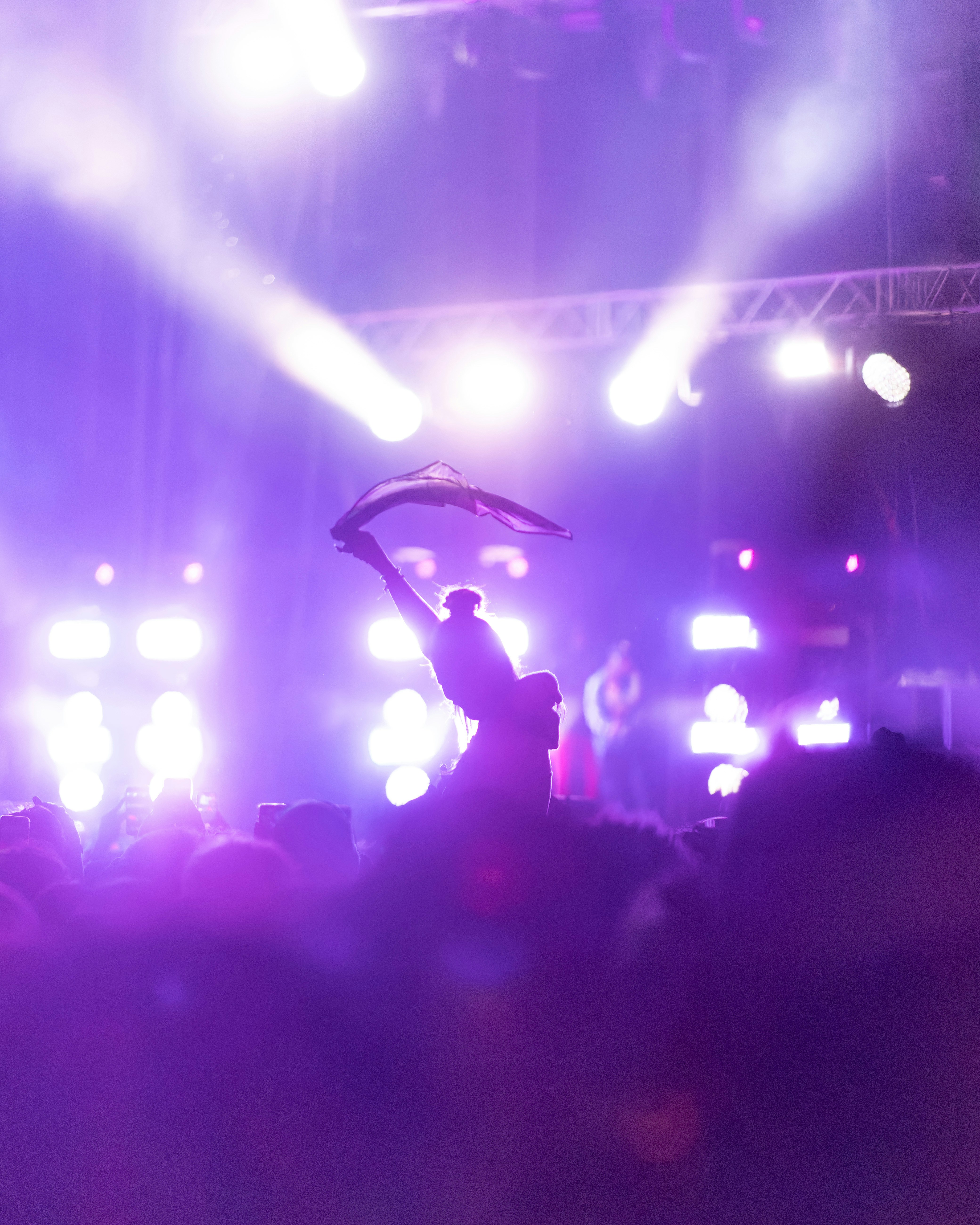 Neon Haze: Silhouette Lifts a Scarf at a Purple-Glow Concert