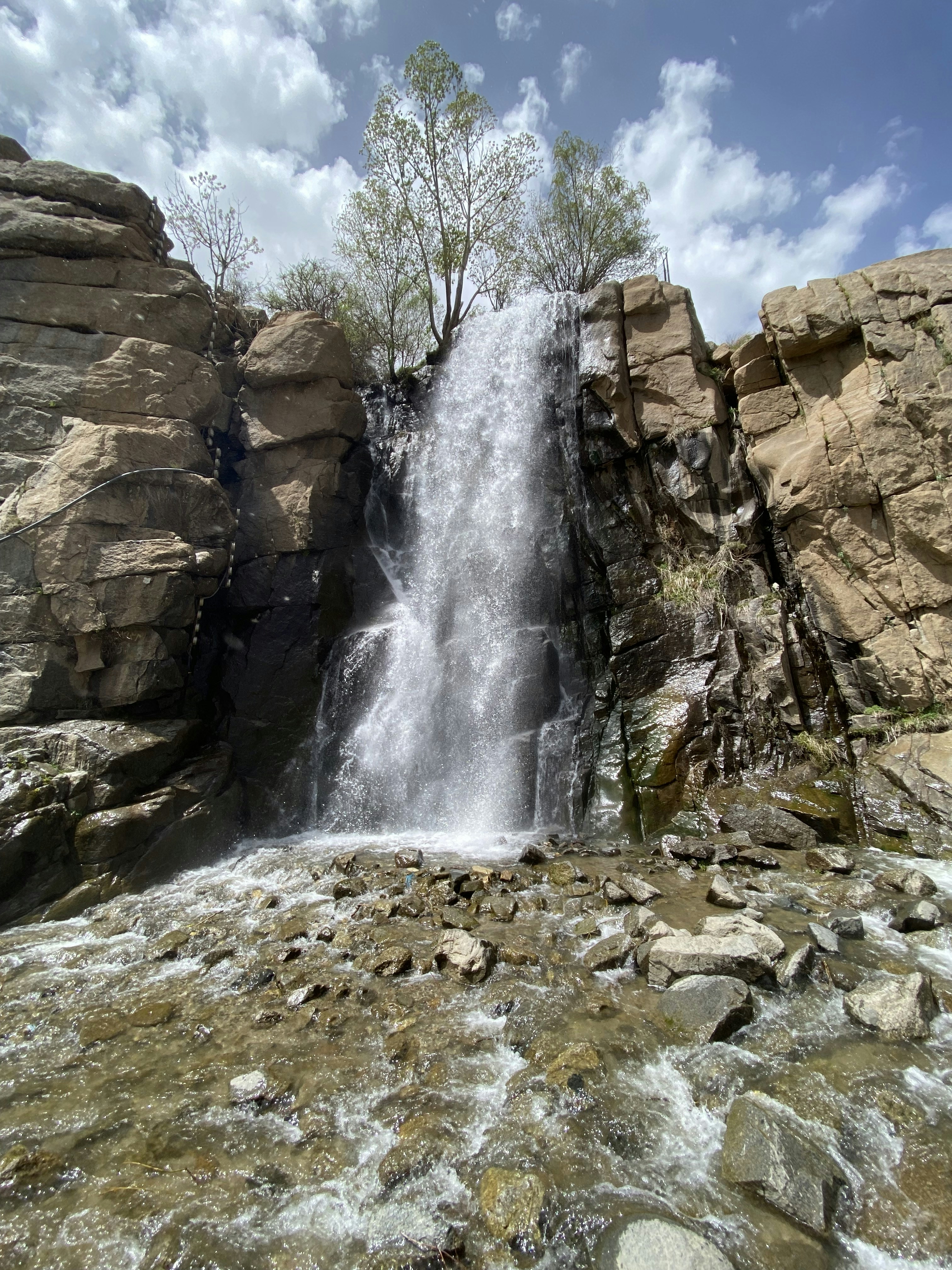 Granite Curtain: A Narrow Waterfall Between Cliff Faces Under Open Sky