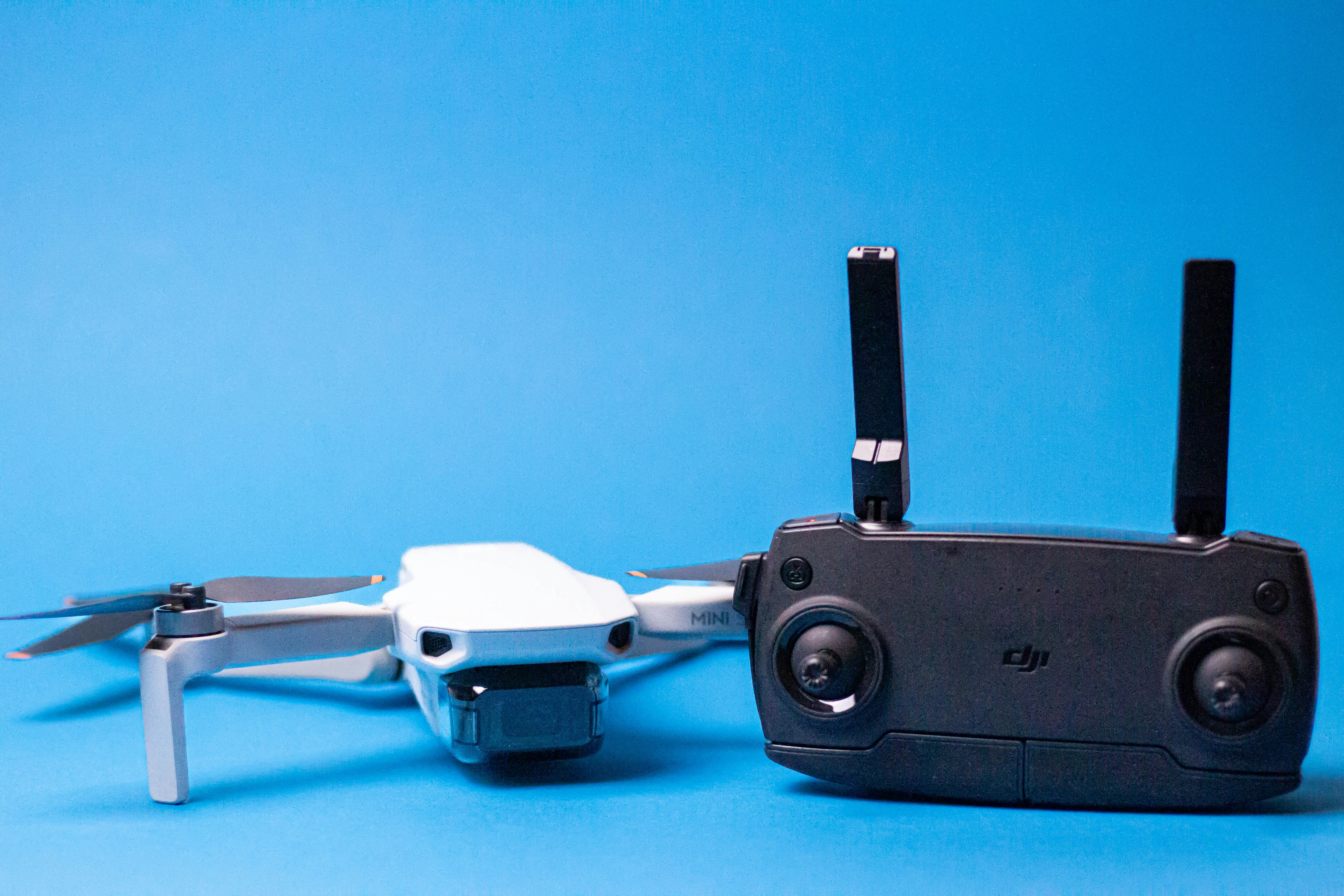 Drone and controller positioned against a vibrant blue background, showcasing modern technology in aerial photography.