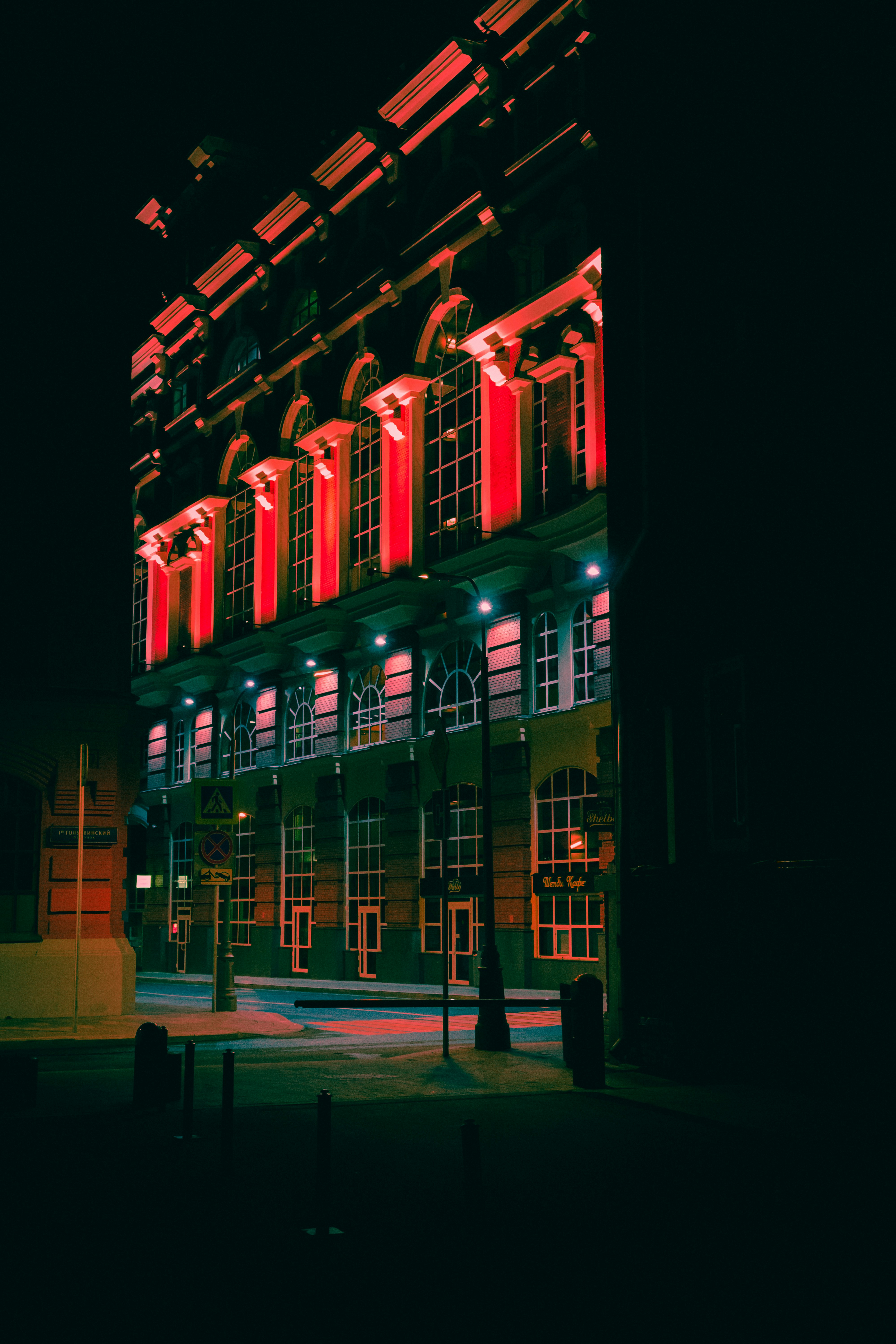 Historic building facade illuminated by vibrant red and green lights at night.