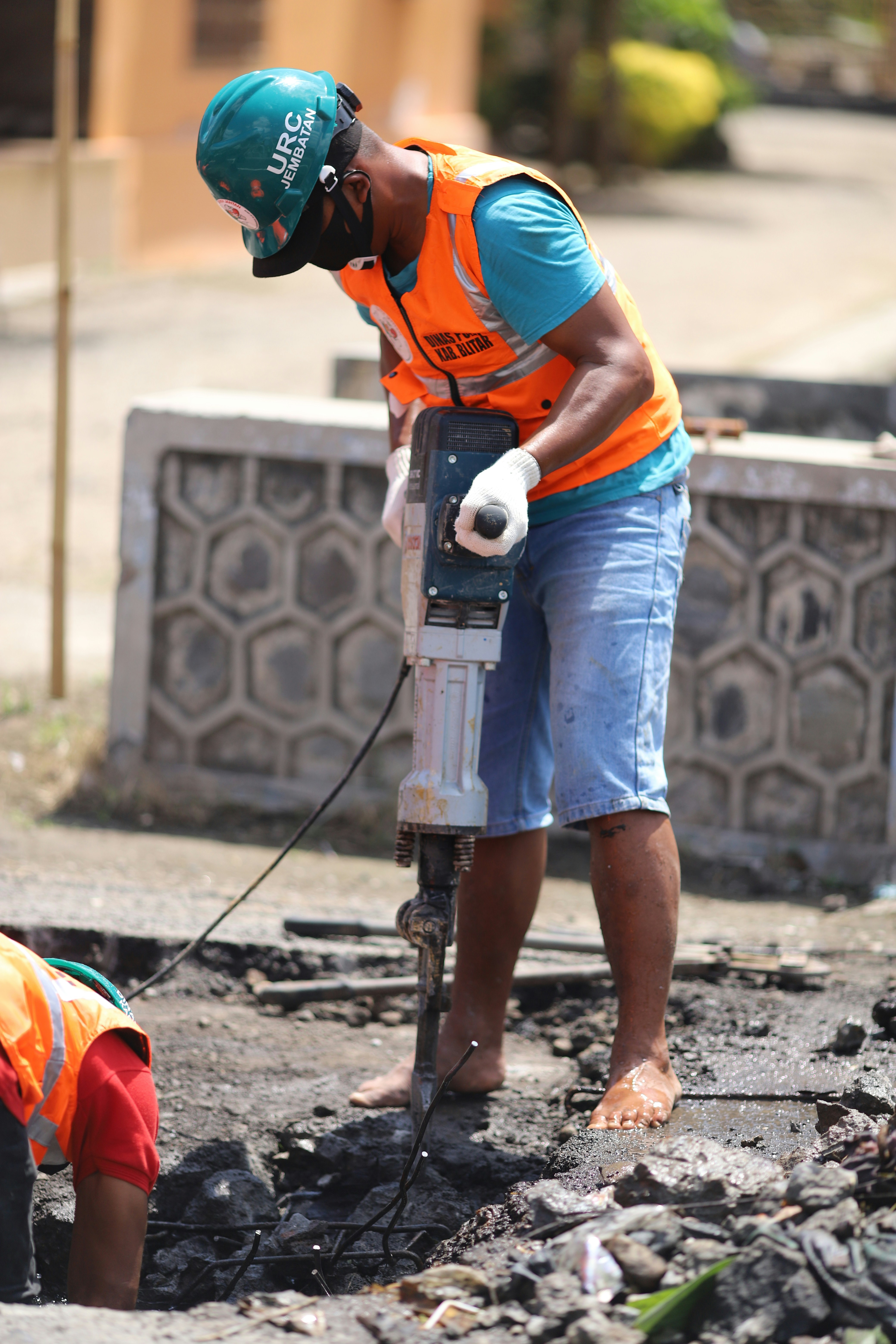 Worker in Orange Vest Drills into Ground with Portable Jackhammer