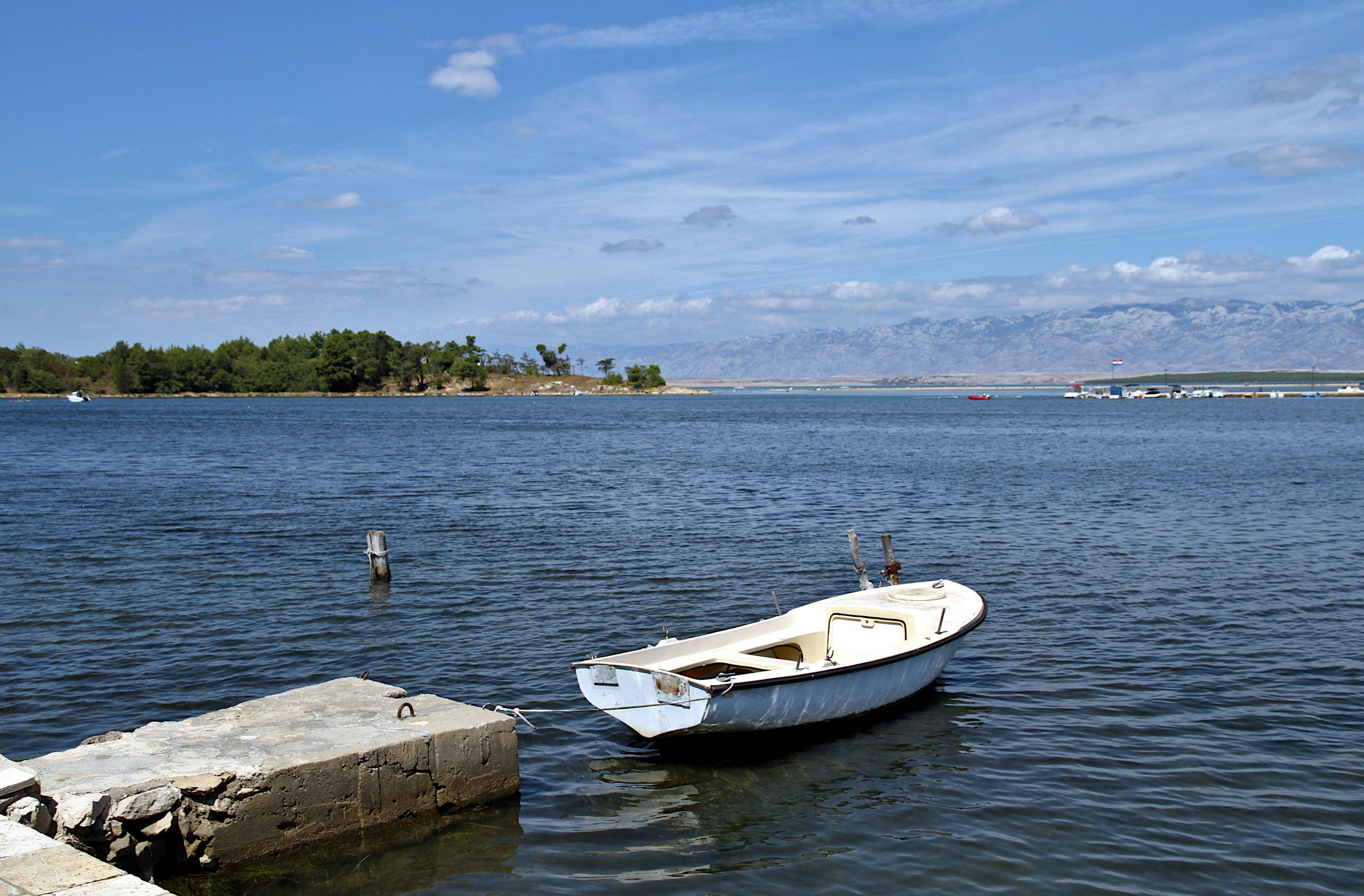 Glassy Lake: A lone rowboat at the edge of a tranquil blue expanse