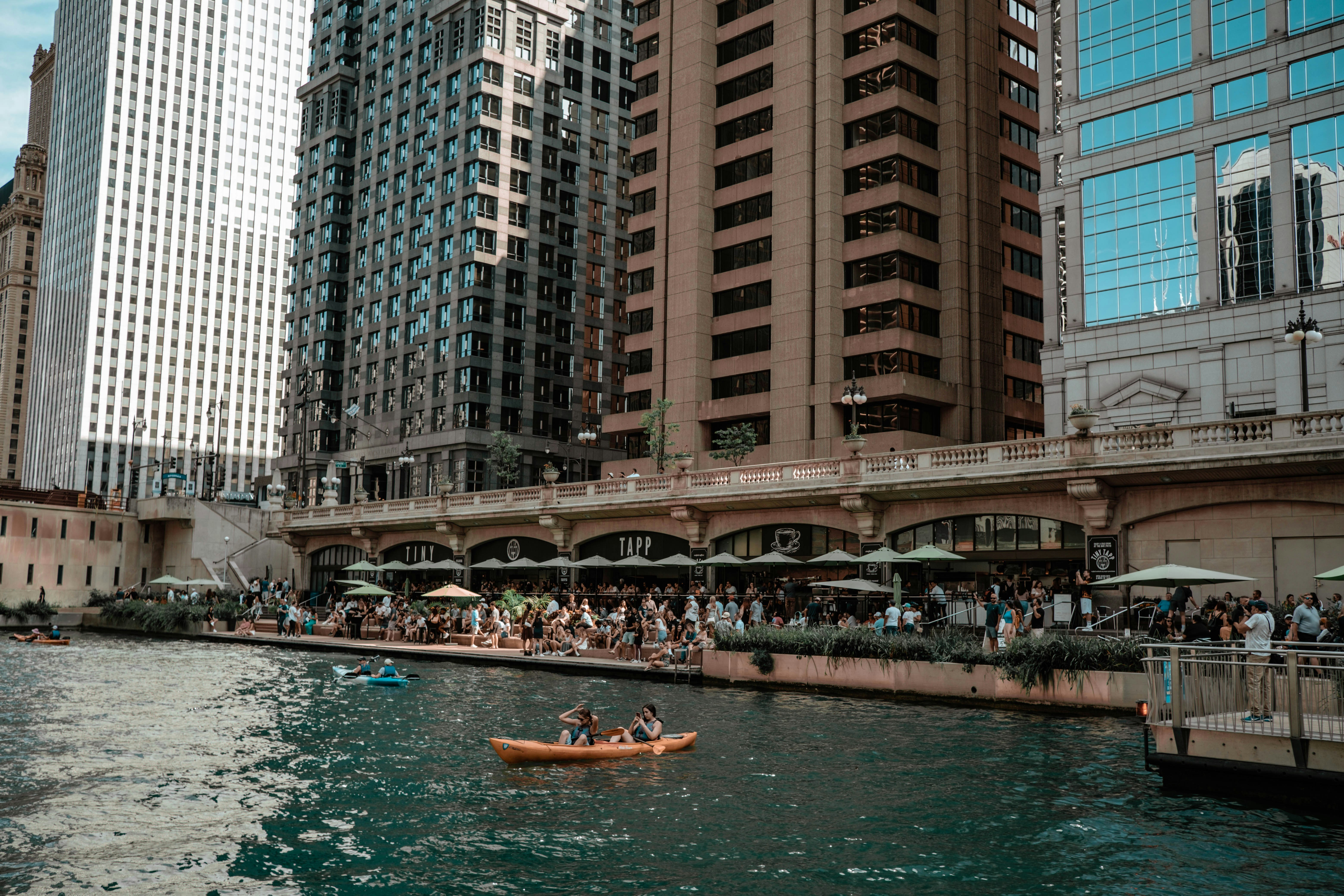 Foto Un grupo de personas en kayaks en un río entre edificios – Imagen ...
