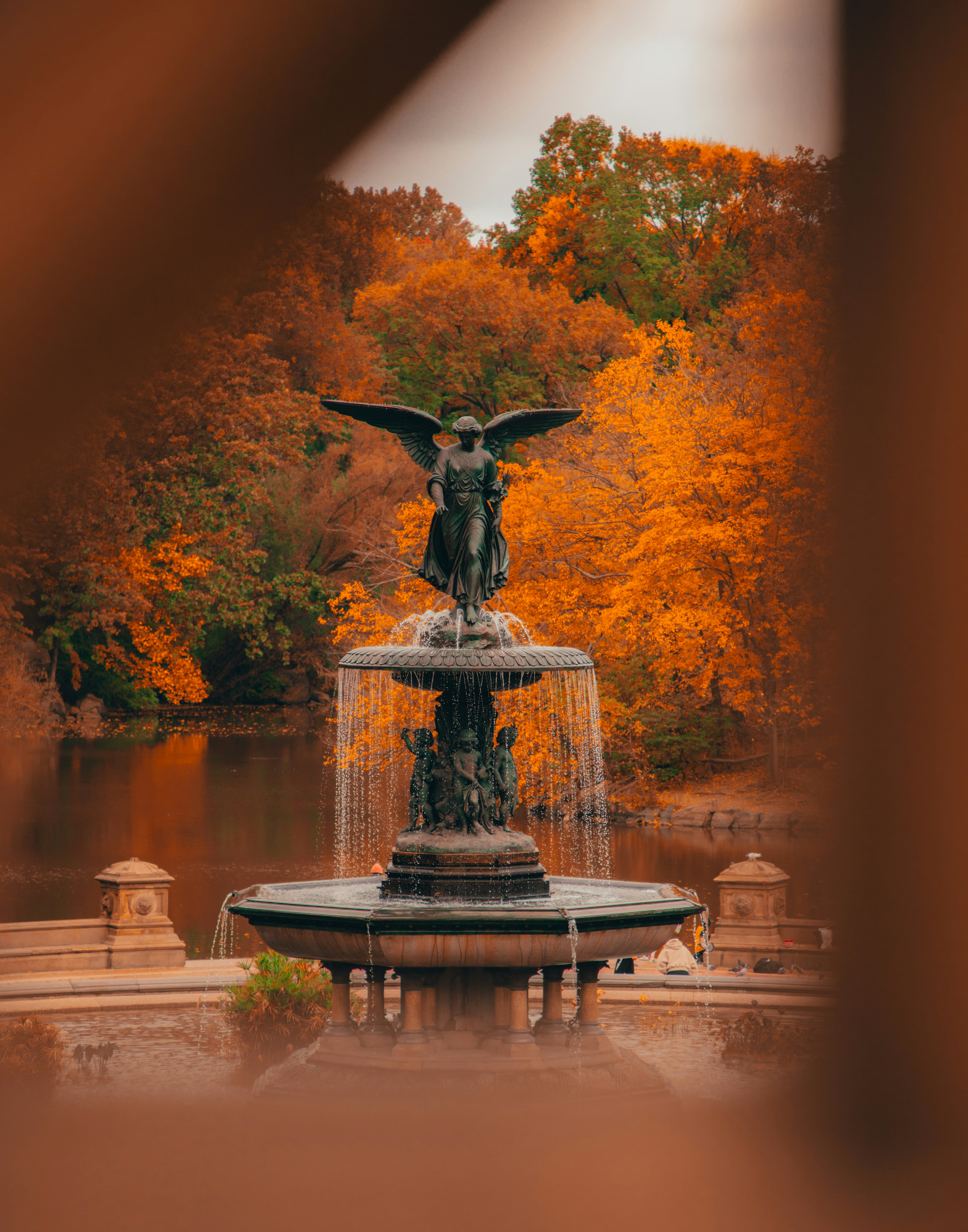 Autumn Sentinel: Angel on a Cascading Fountain Amid Amber Trees