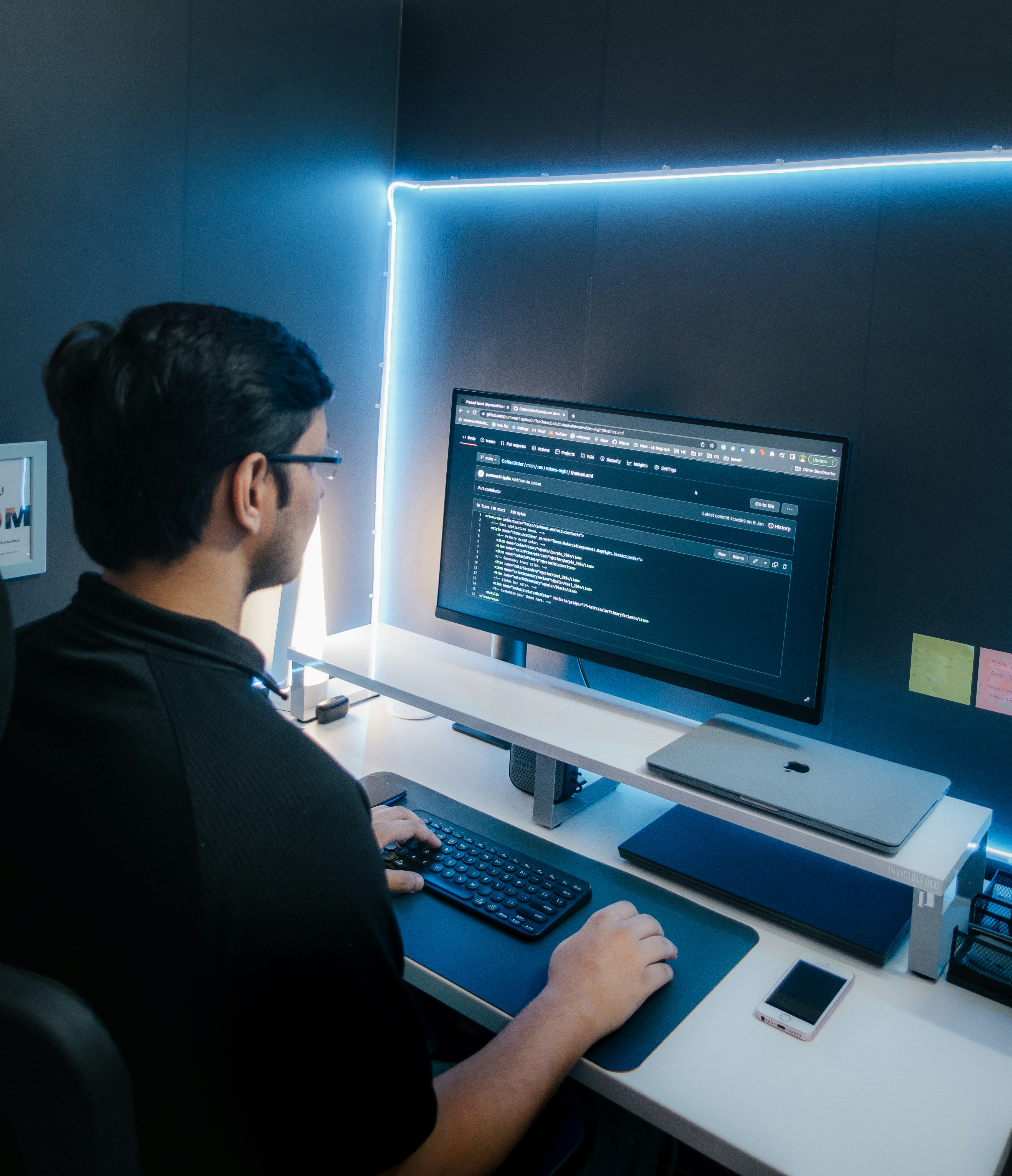 A person sitting at a desk looking at a computer screen photo – Free ...