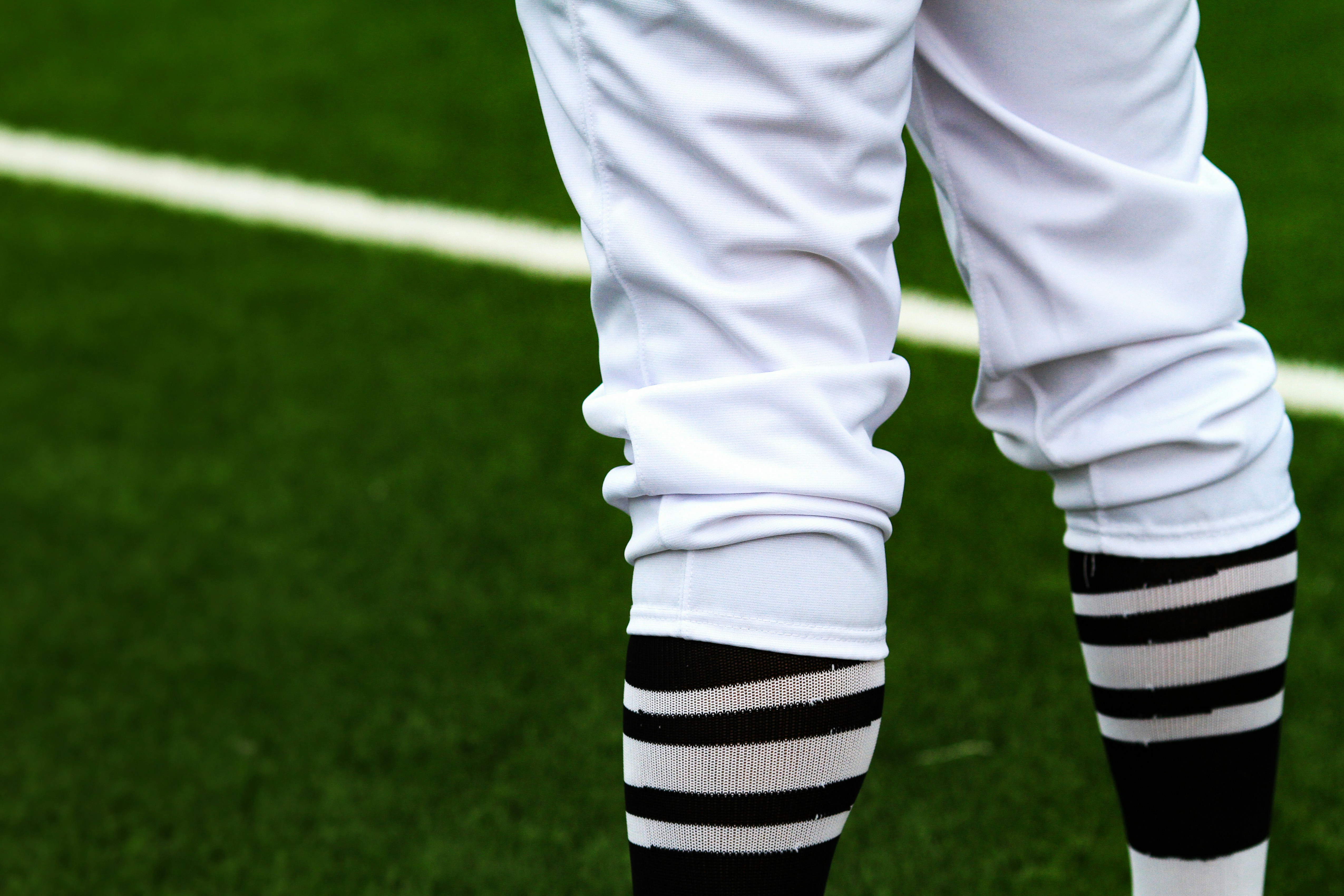 A person's legs in a white uniform on a green field photo – Free ...
