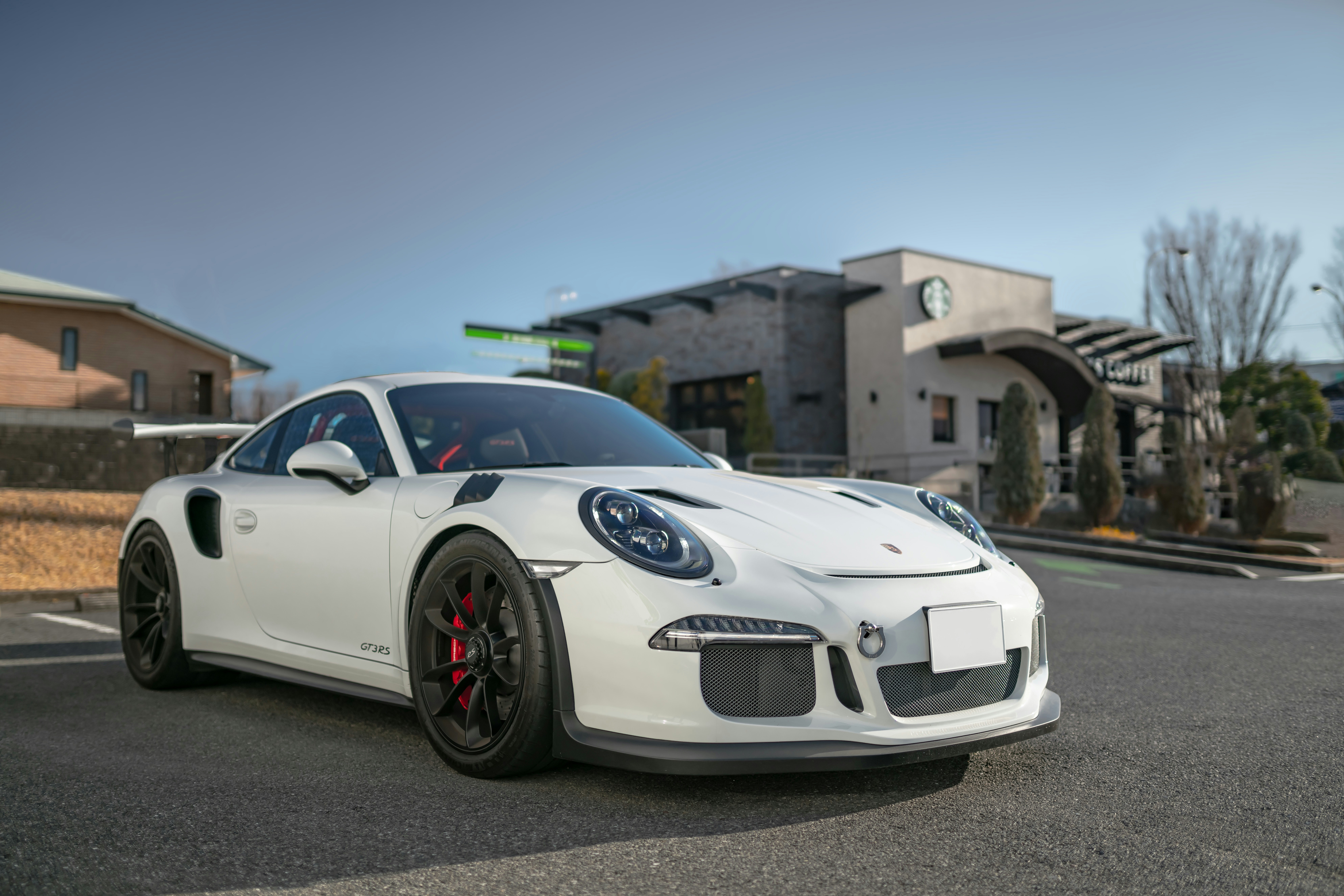 White Porsche 991 GT3 RS parked in front of a modern building on a clear day.