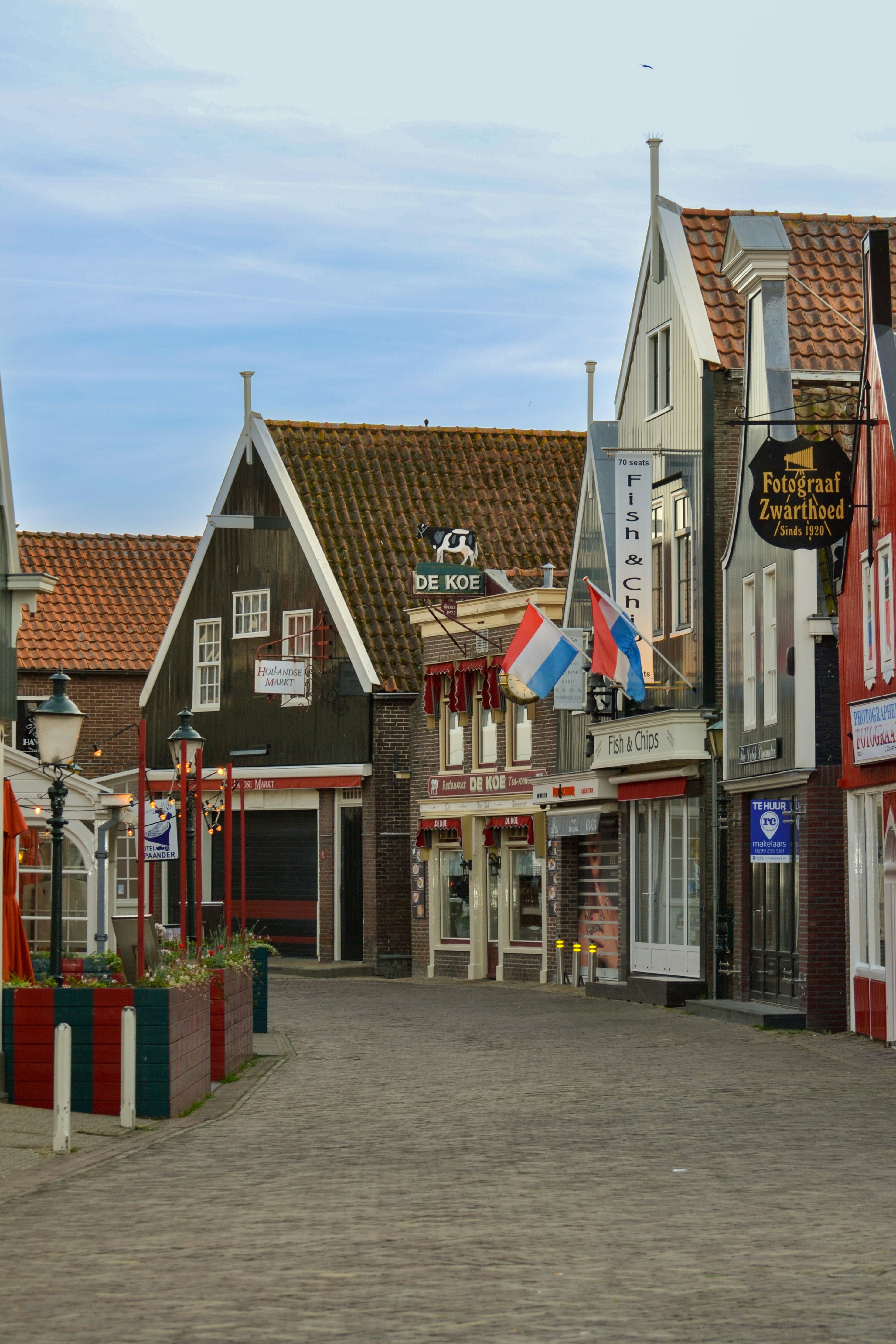 Quaint street lined with traditional Dutch architecture, featuring shops and flags, inviting exploration. A perfect blend of culture and coastal charm.