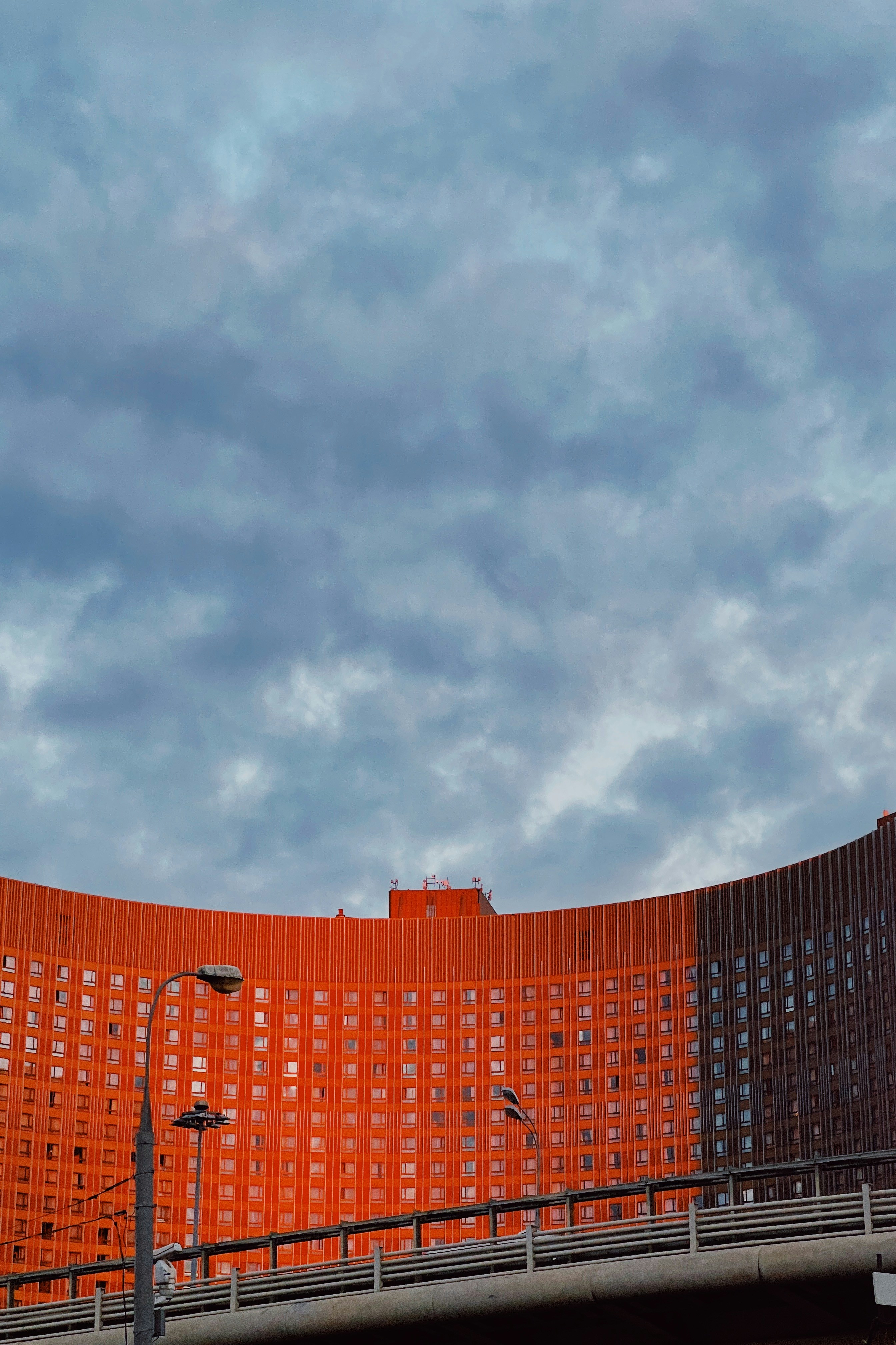 Curved Brick Facade Beneath a Clouded Sky