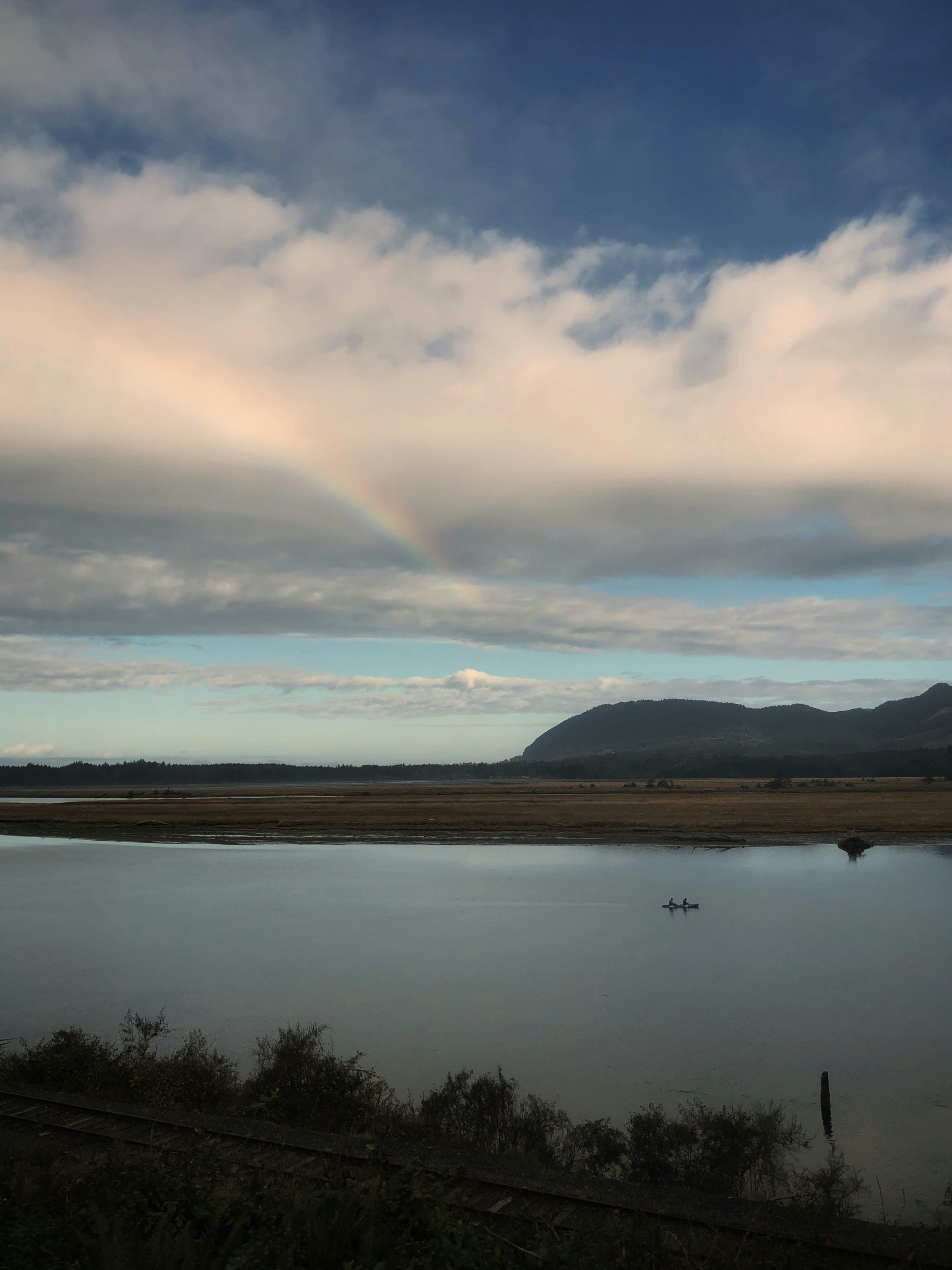 Rainbow over the river: tranquil valley with distant hills