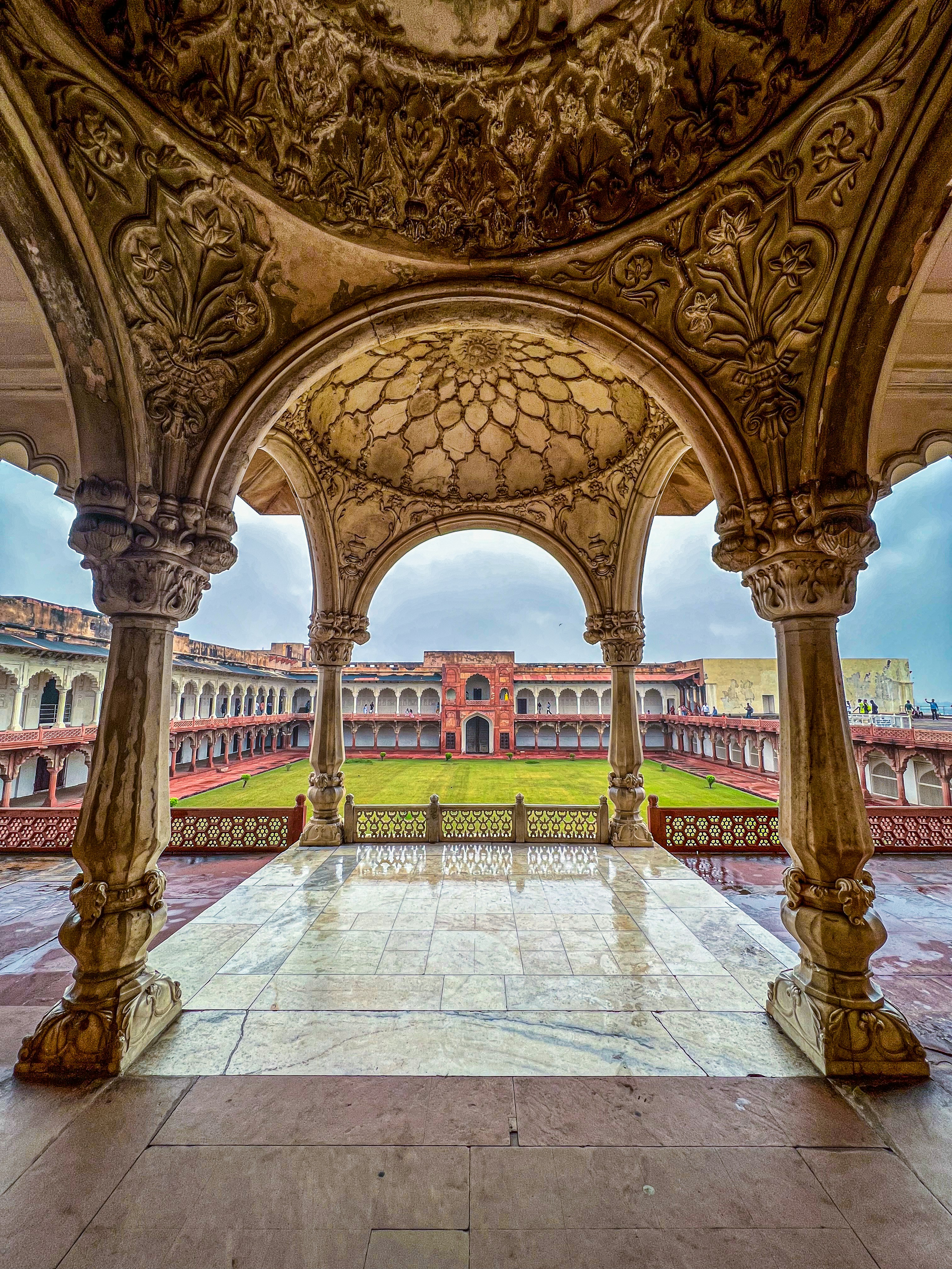 Intricate arches frame a lush courtyard, showcasing the grandeur of historical architecture. The scene invites exploration of the detailed craftsmanship and serene surroundings.
