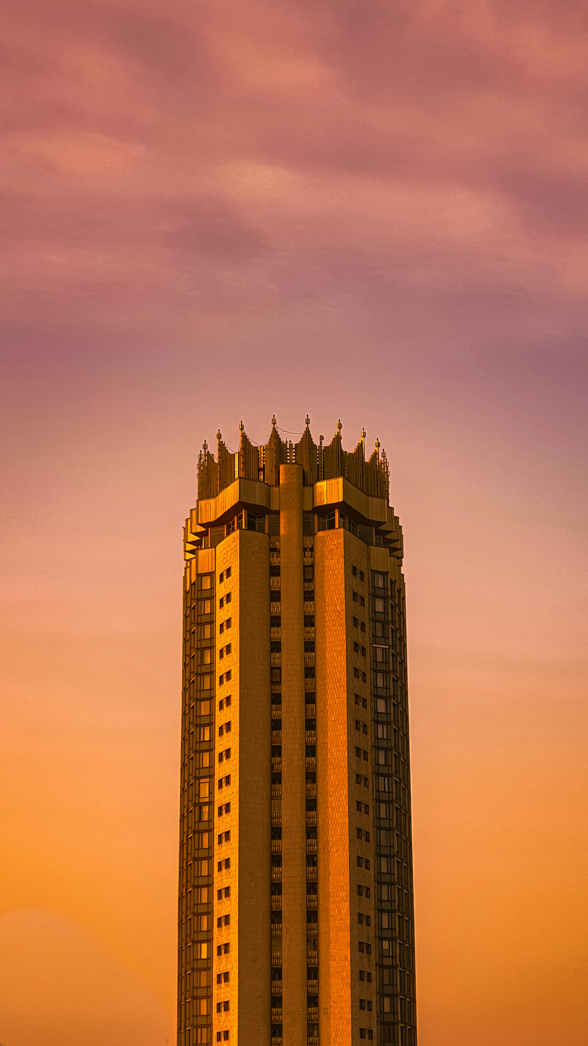 a tall building with a pink sky