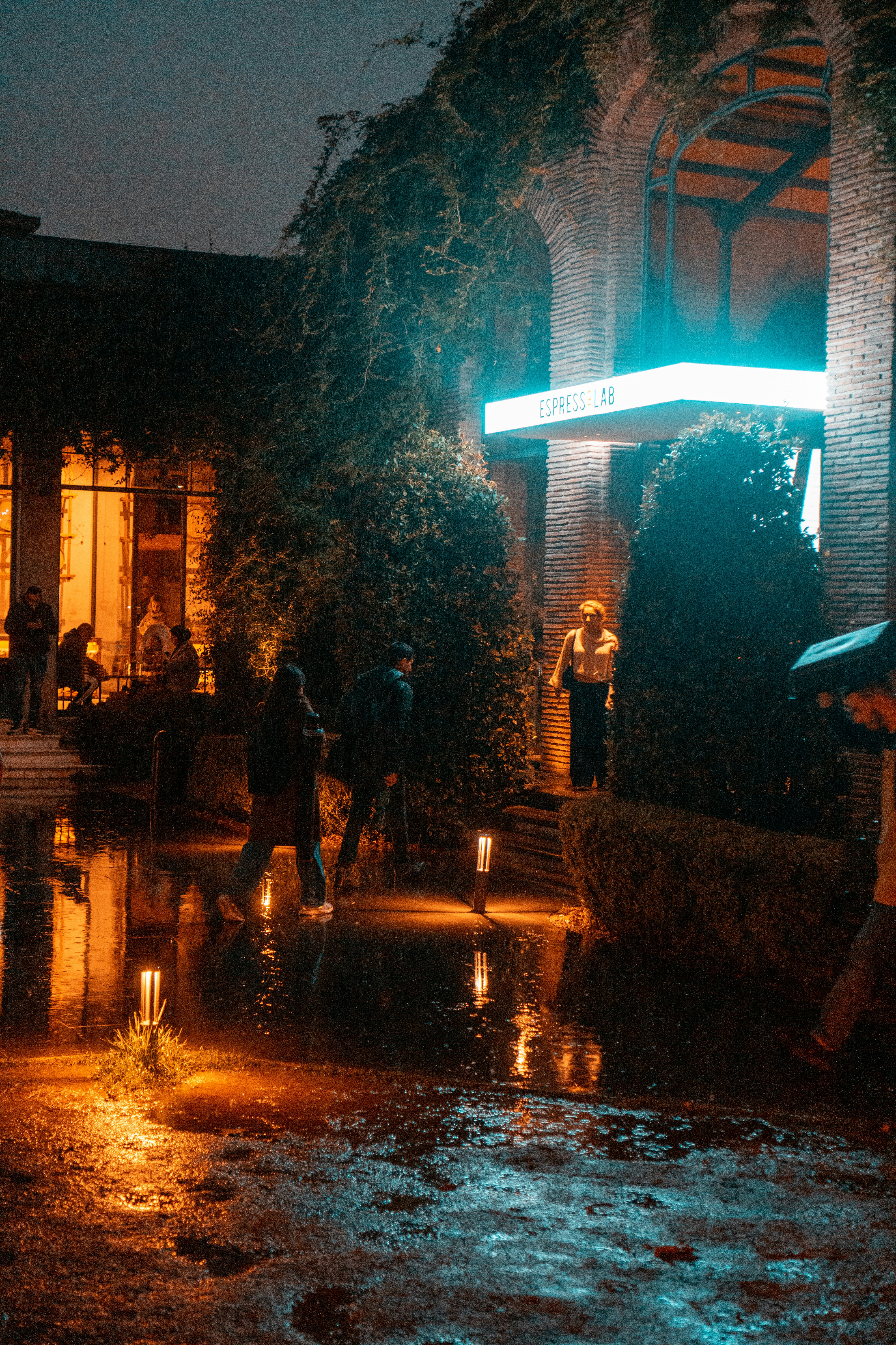 A group of people standing outside a building with a fountain in front ...