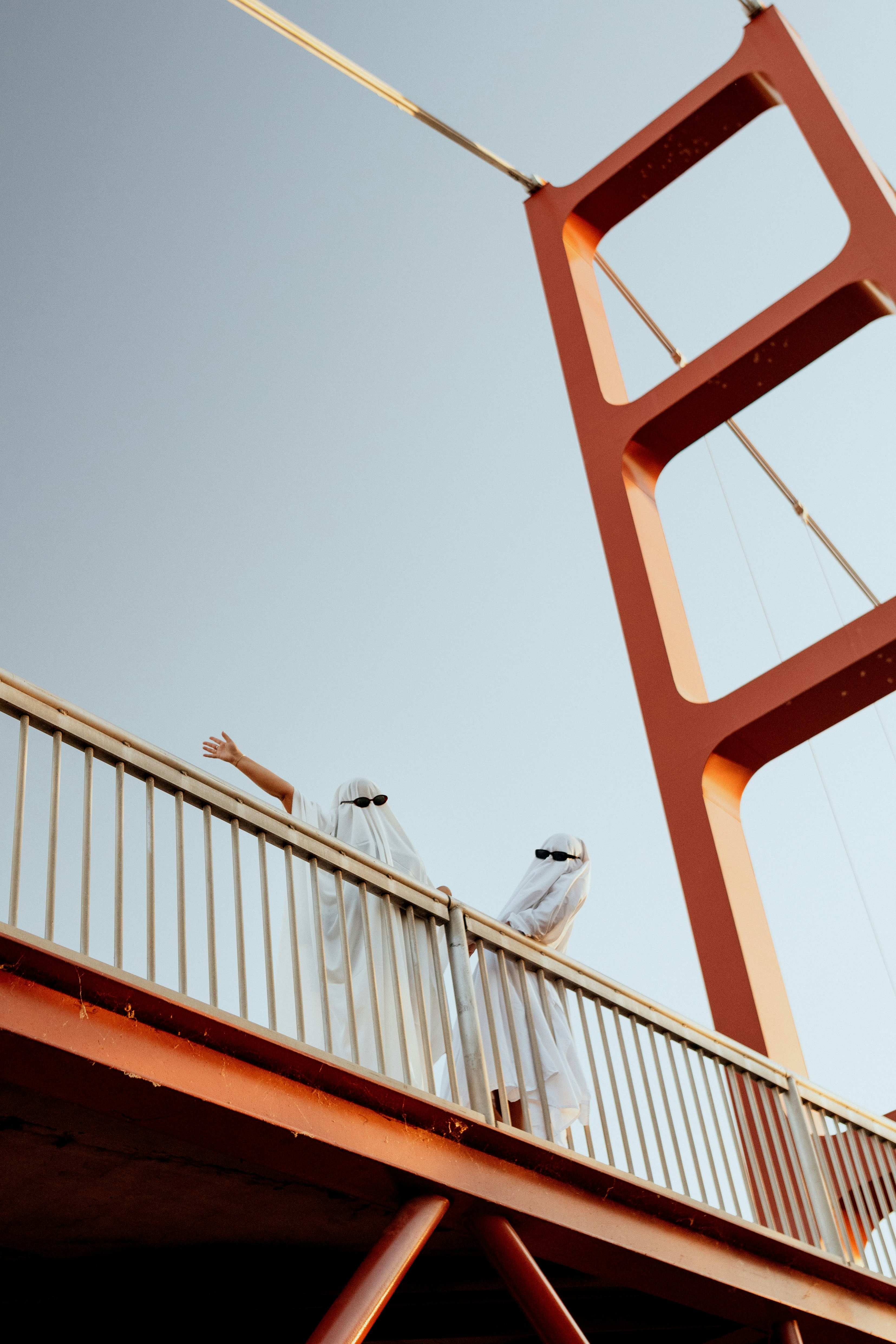 Ghosts on the Rust-Orange Span: White-Robed Figures Over a Quiet Bridge