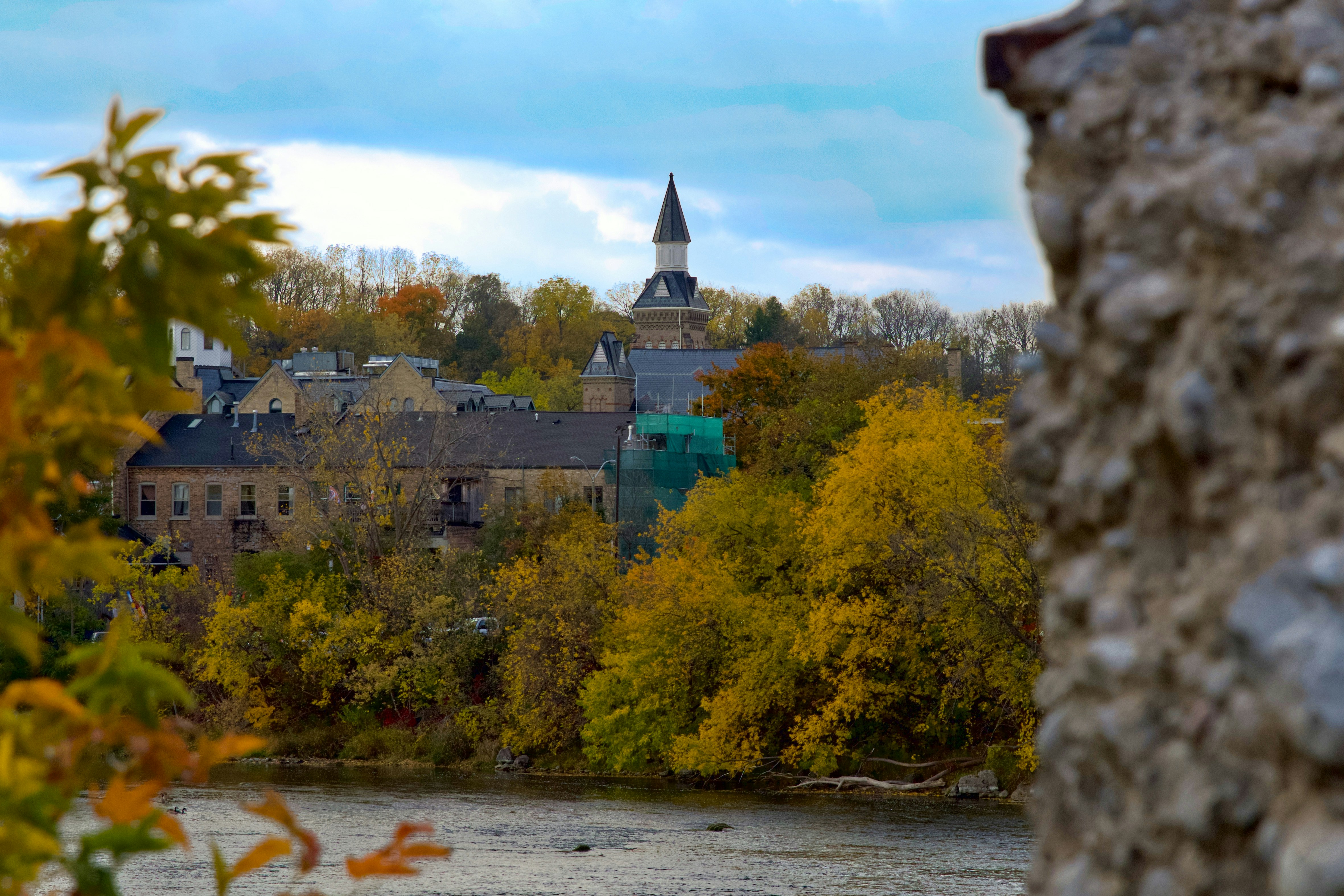 A building with a tower surrounded by trees and water photo – Free ...