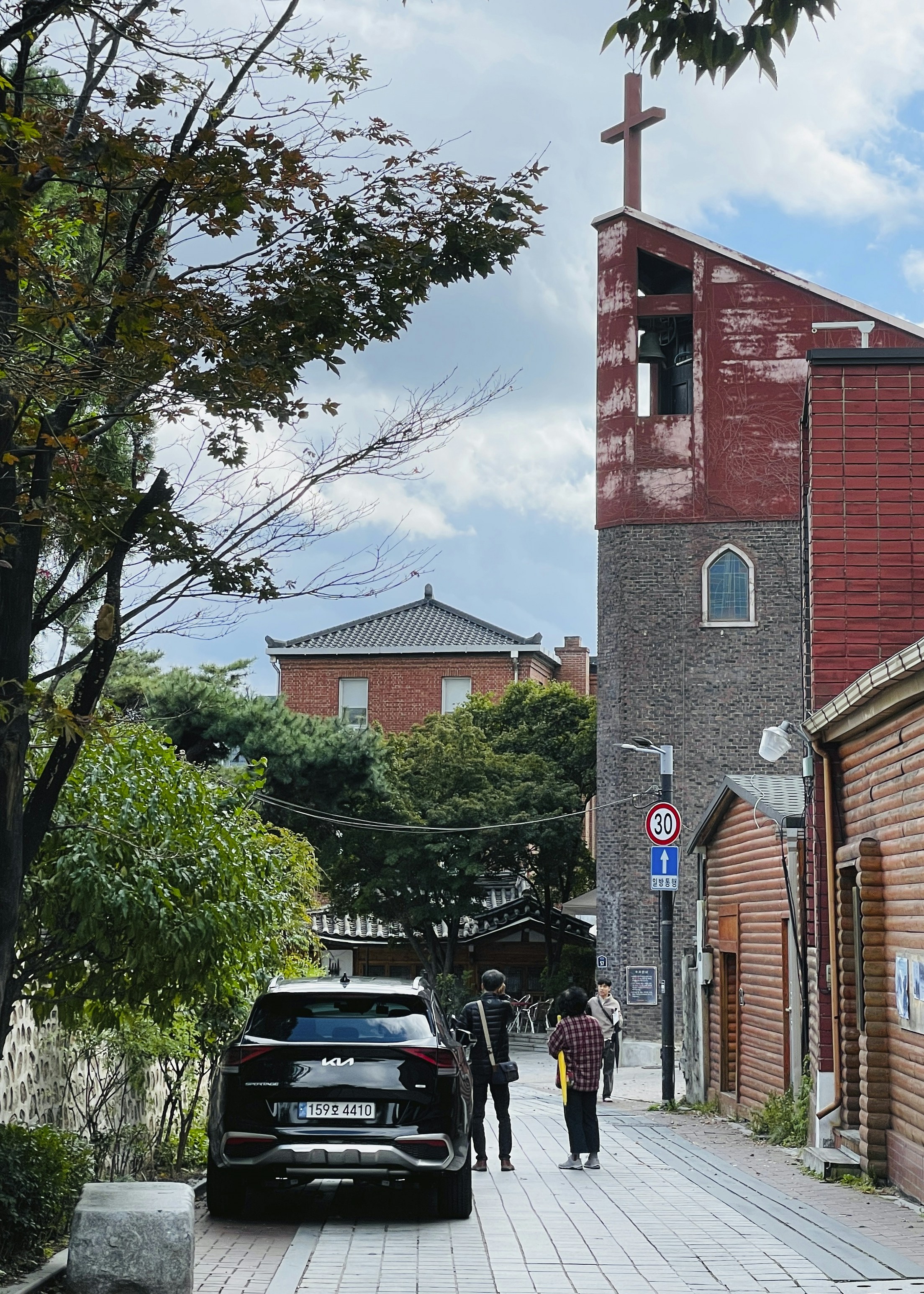Cross-Topped Church Corner: A Quiet Street Scene in Brick and Foliage