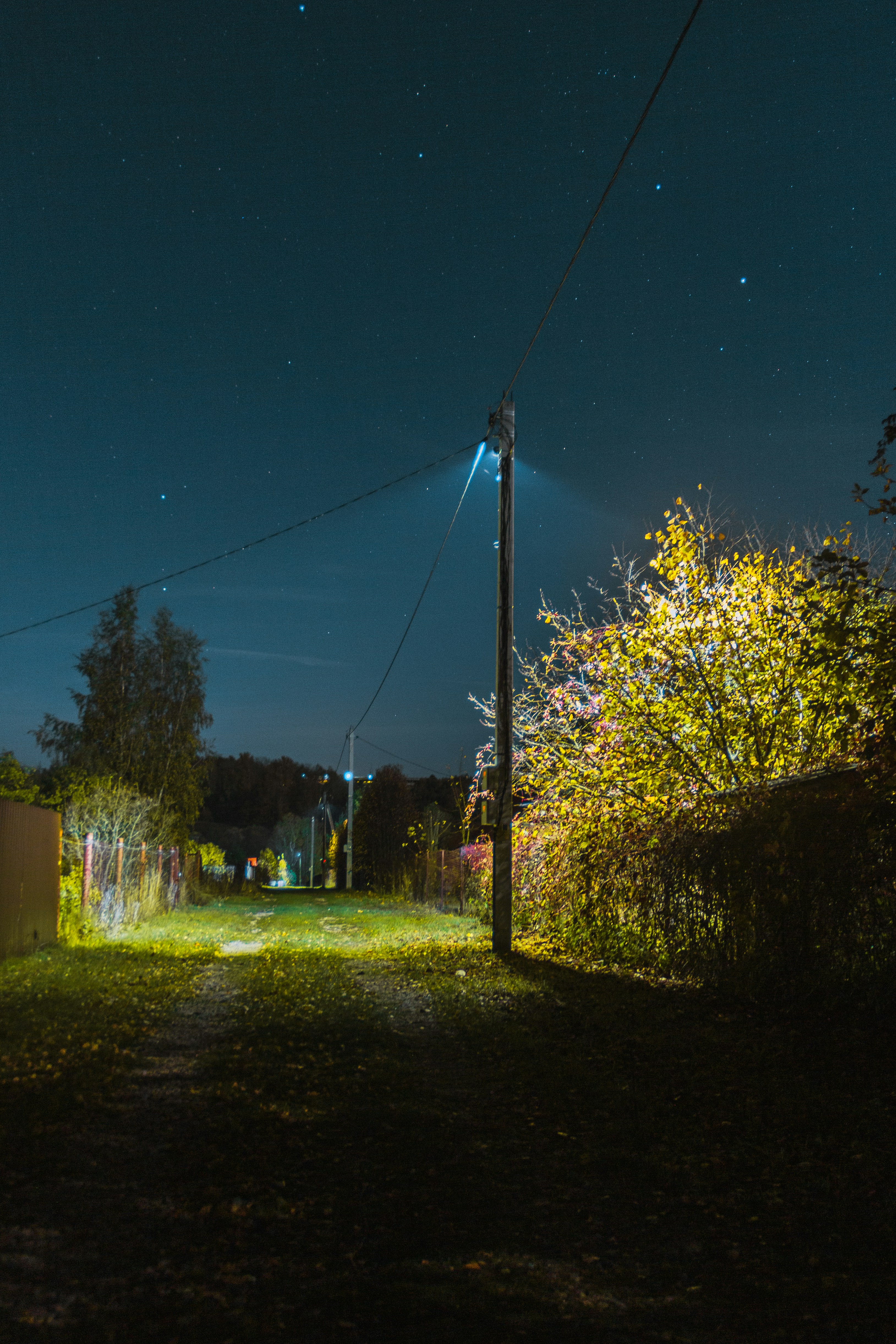 Pole and Starry Lane: A Night Walk Framed by Warm Street Light