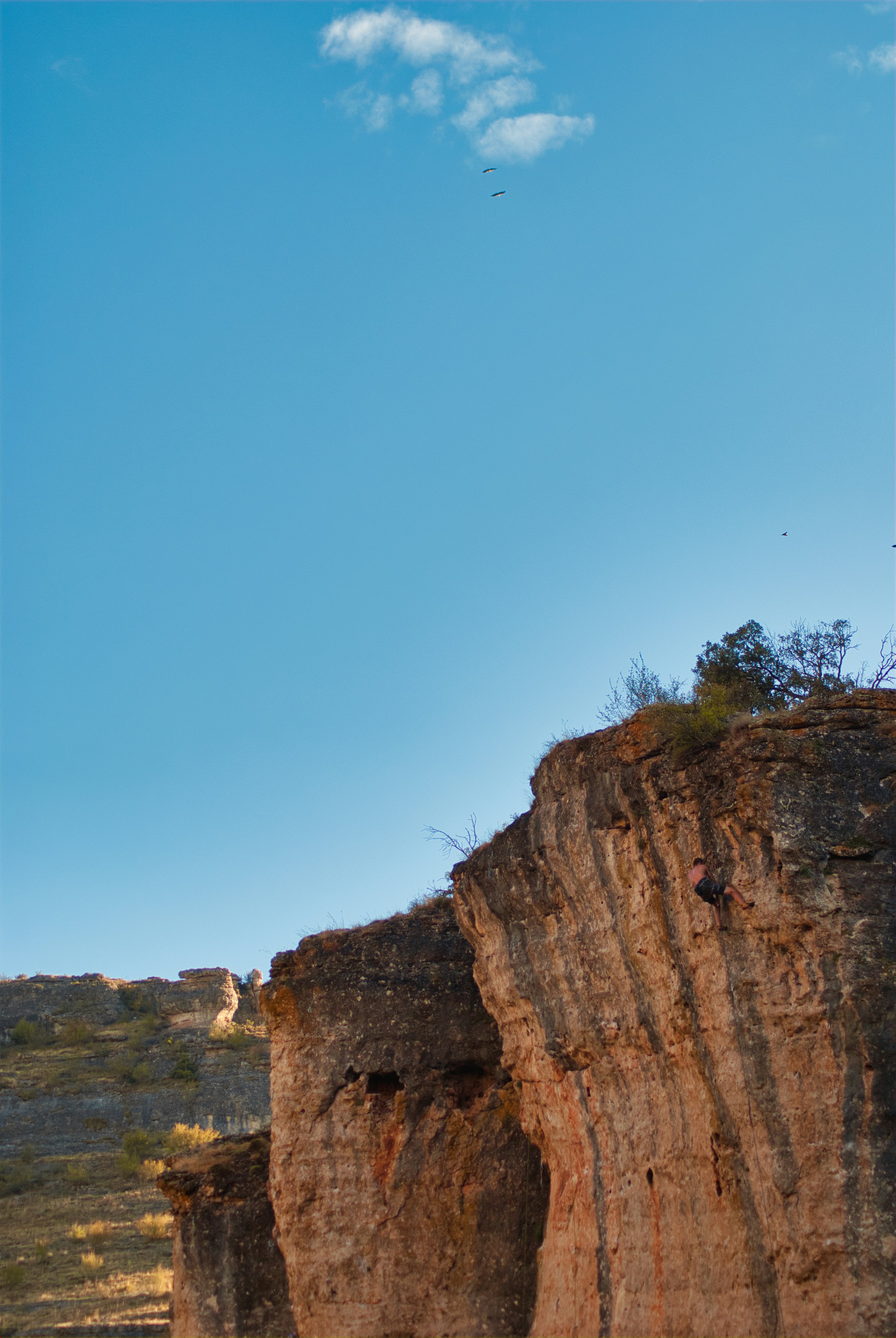 Solitary Climber on a Sun-Burnished Cliff Beneath a Boundless Blue