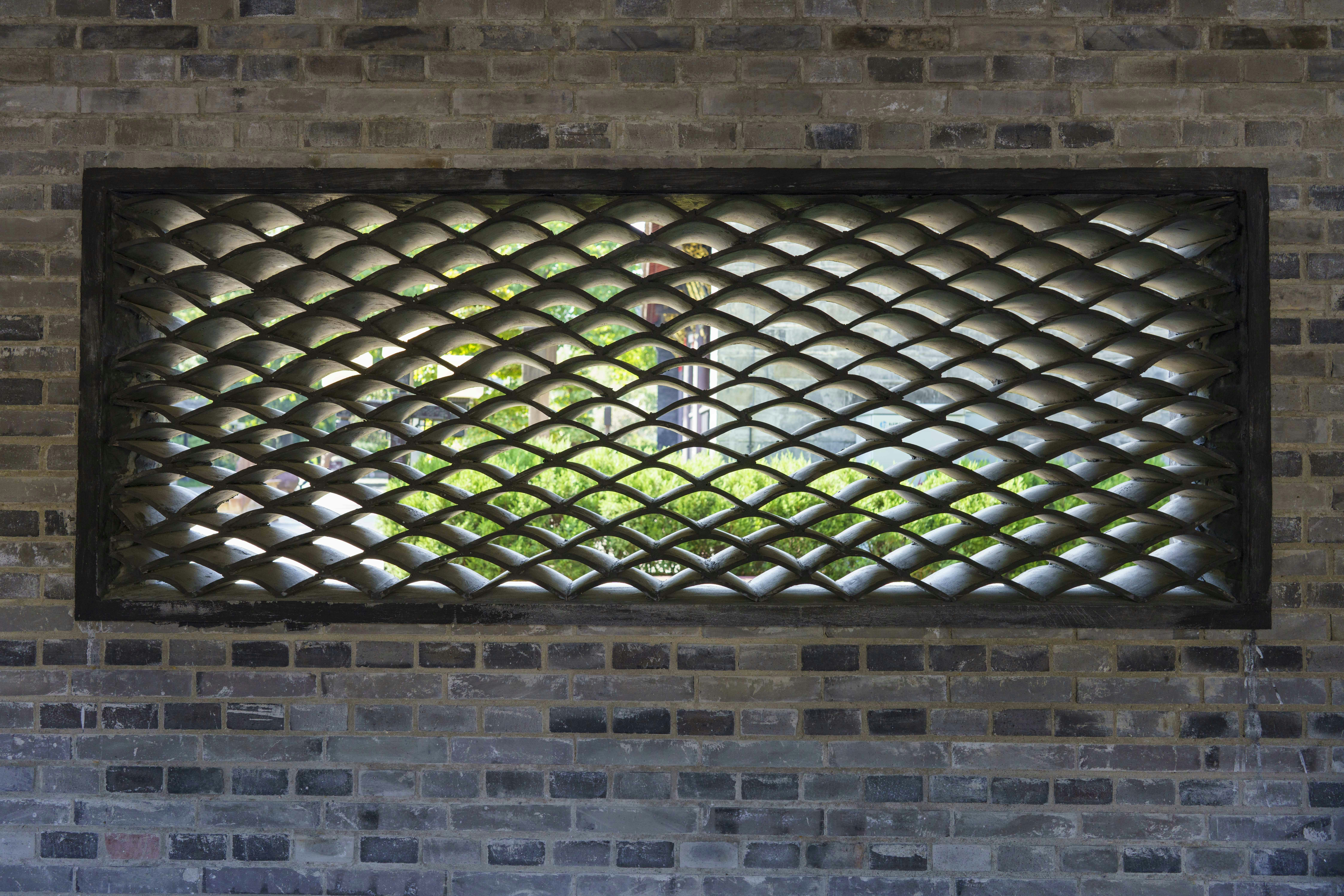 Behind Diamond Mesh: A Quiet Figure in a Brick Frame
