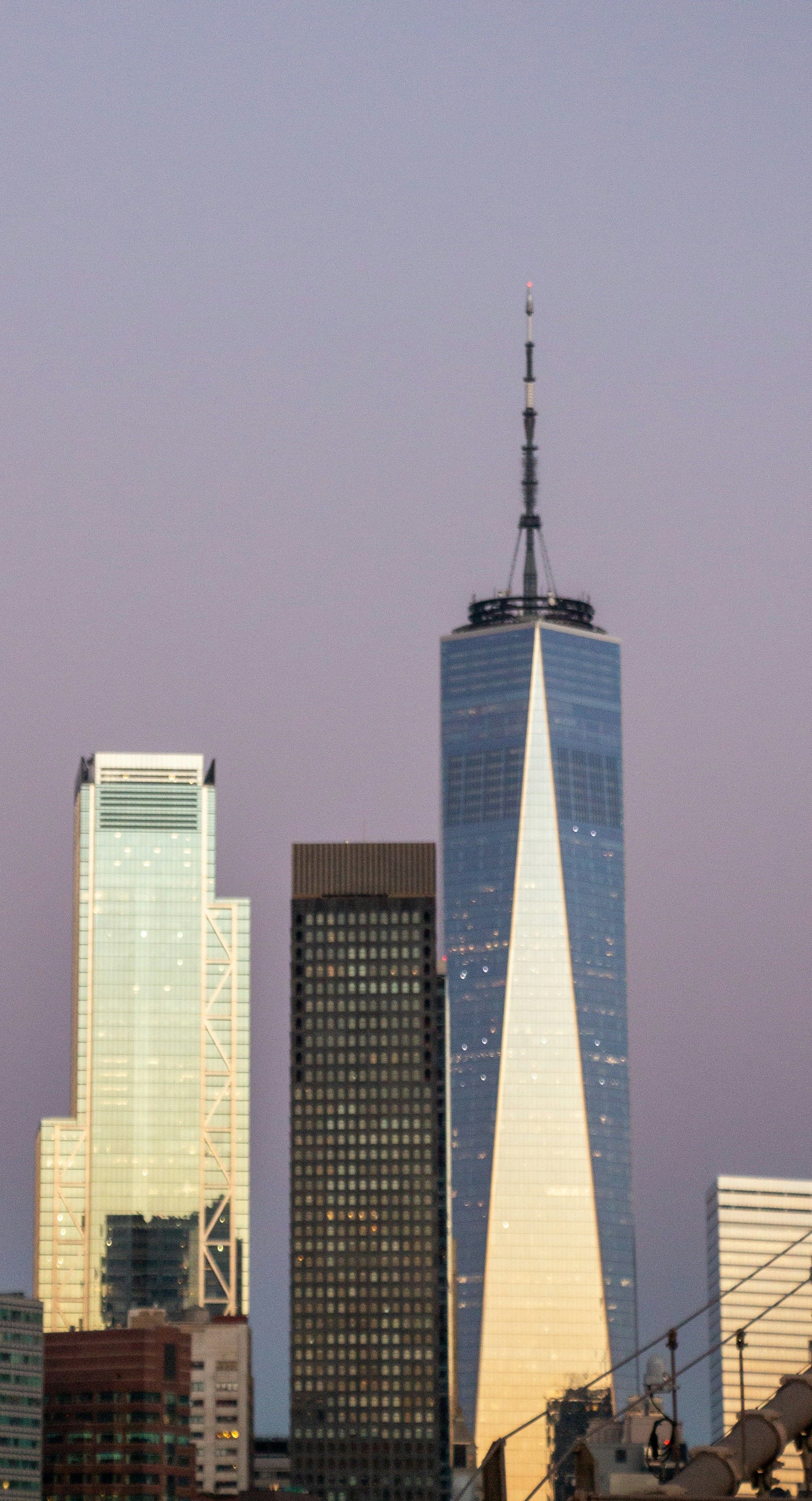 Skyline featuring modern skyscrapers reflecting the soft hues of twilight. The prominent structure showcases a unique architectural design.