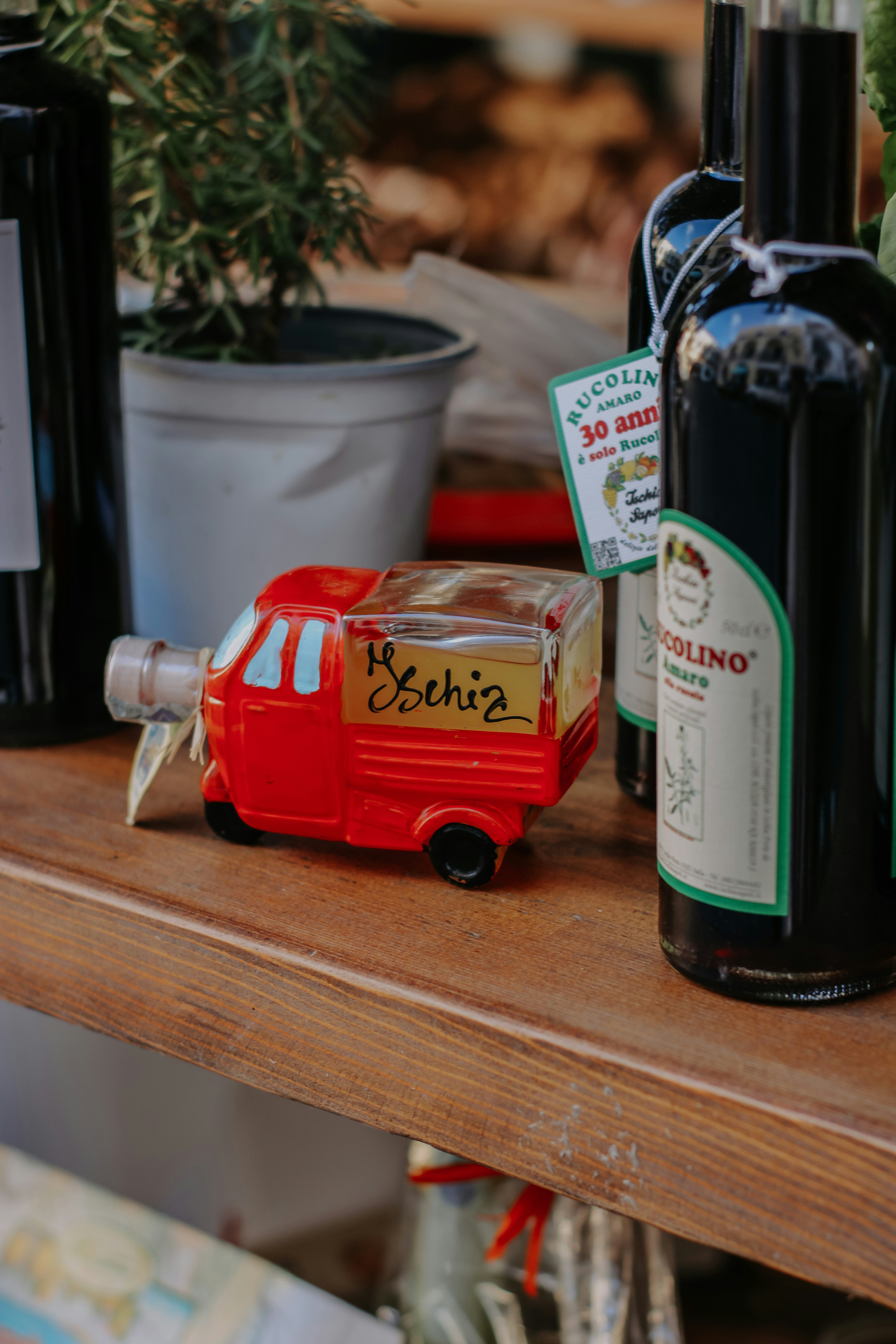 Red Toy Truck Among Dark Bottles on a Rustic Bar Shelf