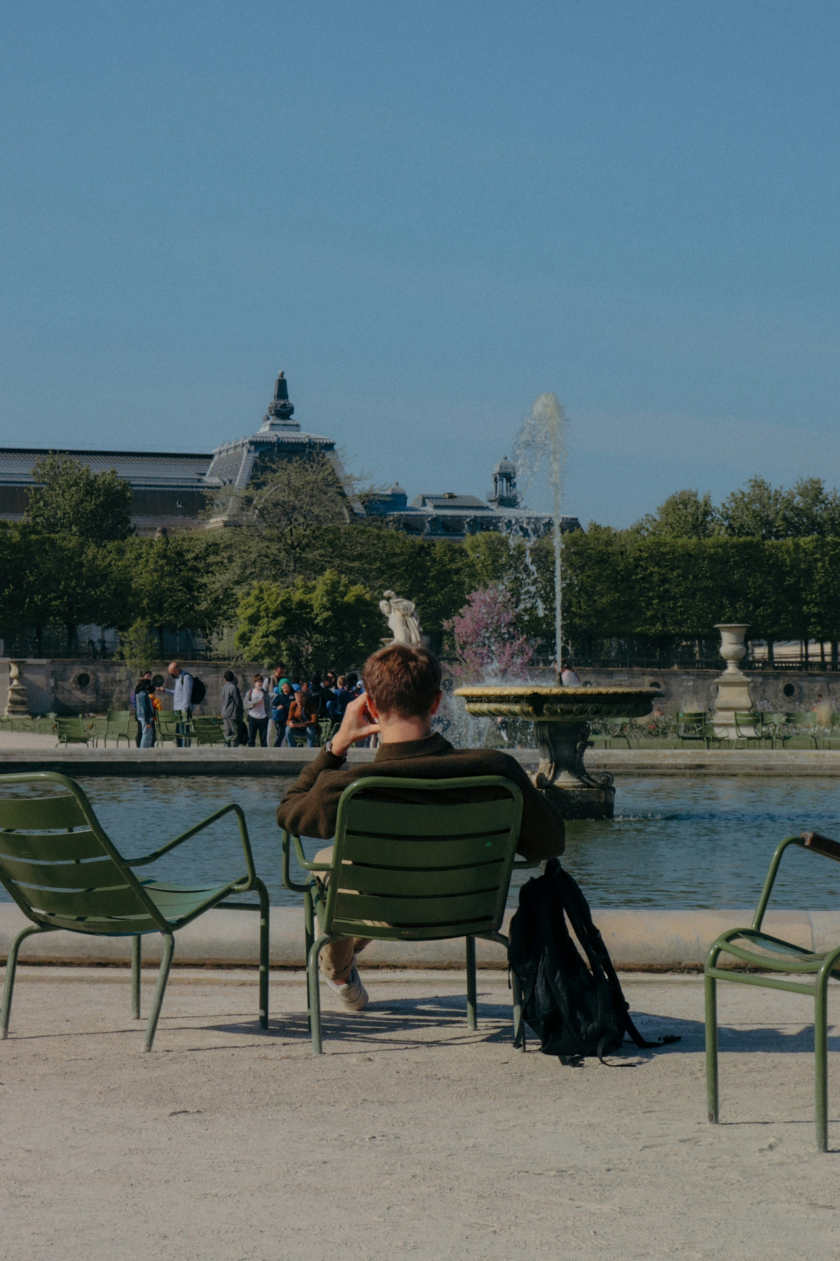 Une personne assise sur une chaise devant une fontaine photo – Photo ...