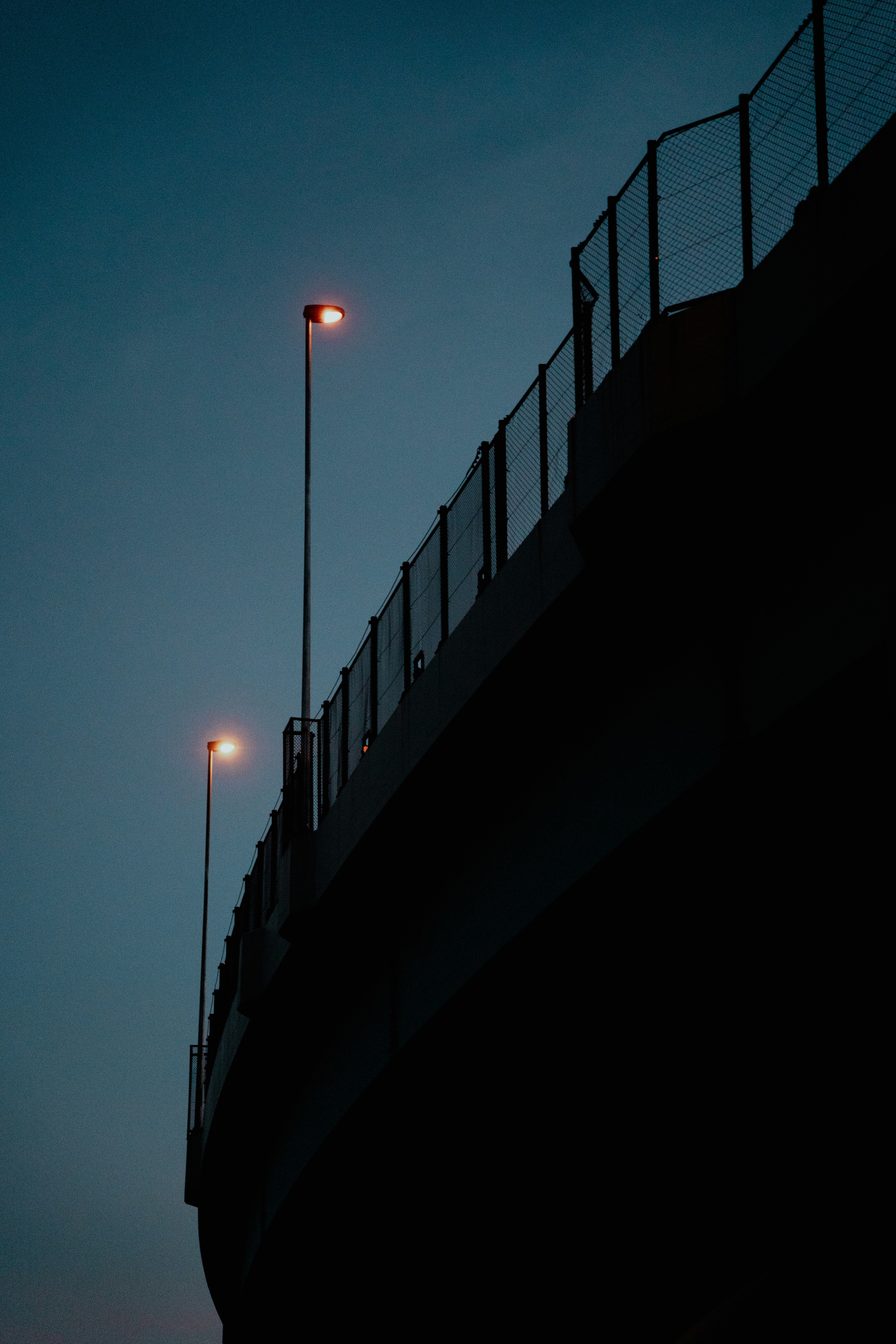 Silhouette of a bridge with streetlights glowing against a twilight sky.