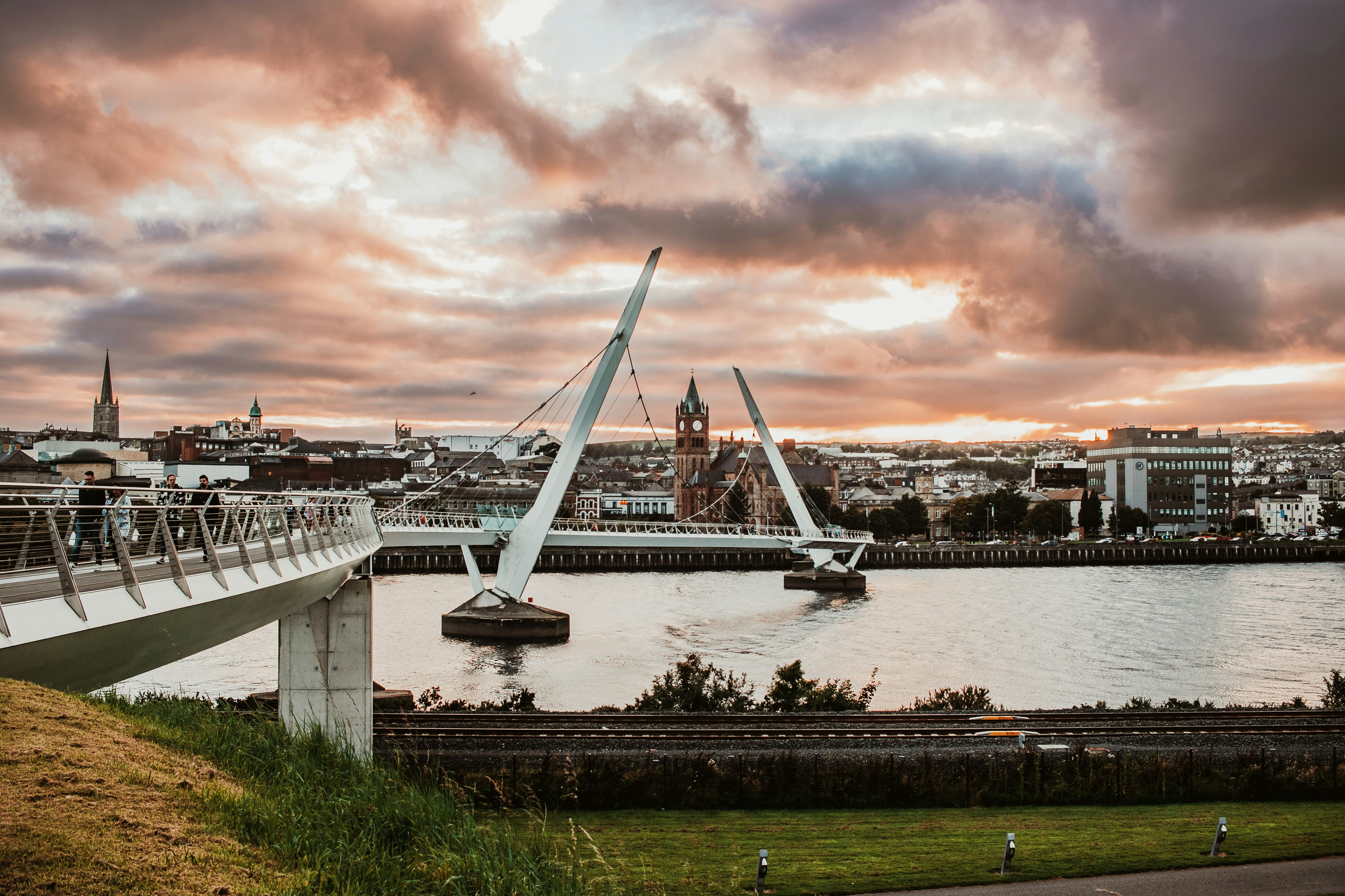 Contemporary bridge structure spanning a river with a dramatic sunset sky in the background.