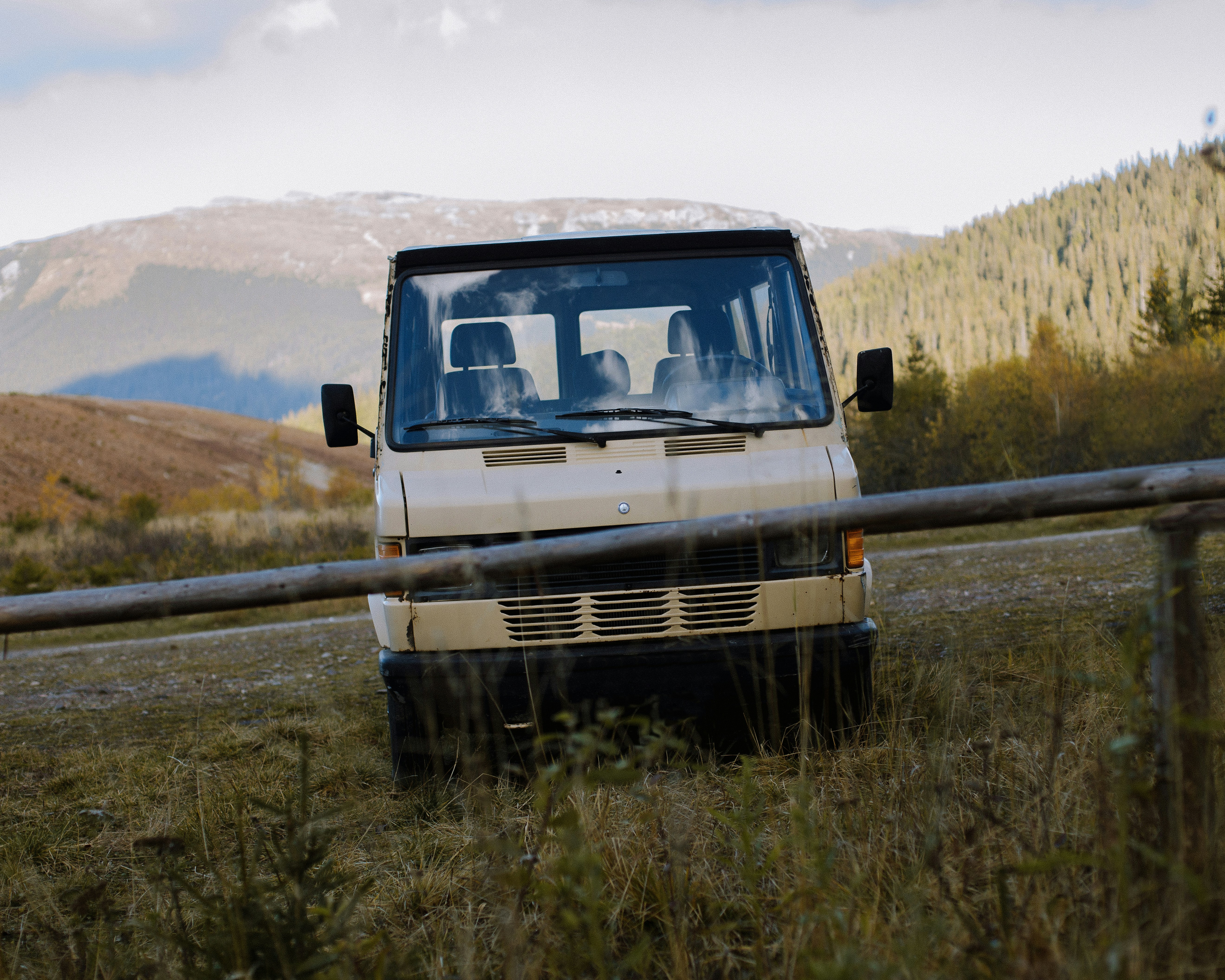 White Van at the Highland Fence: Quiet Ride Toward Snow-Dusted Peaks